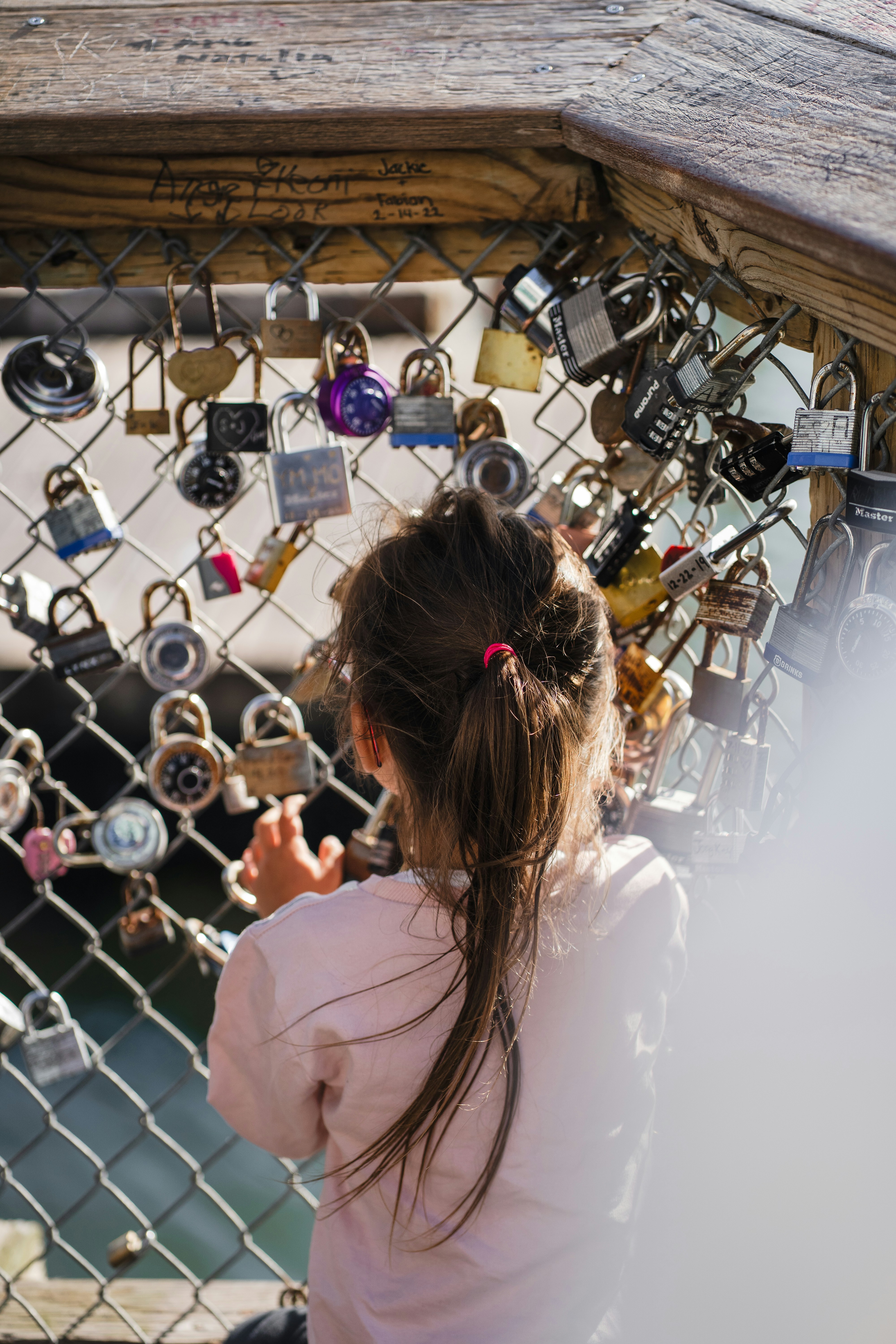 Locks of Memory: A Girl in Front of a Padlock Bridge