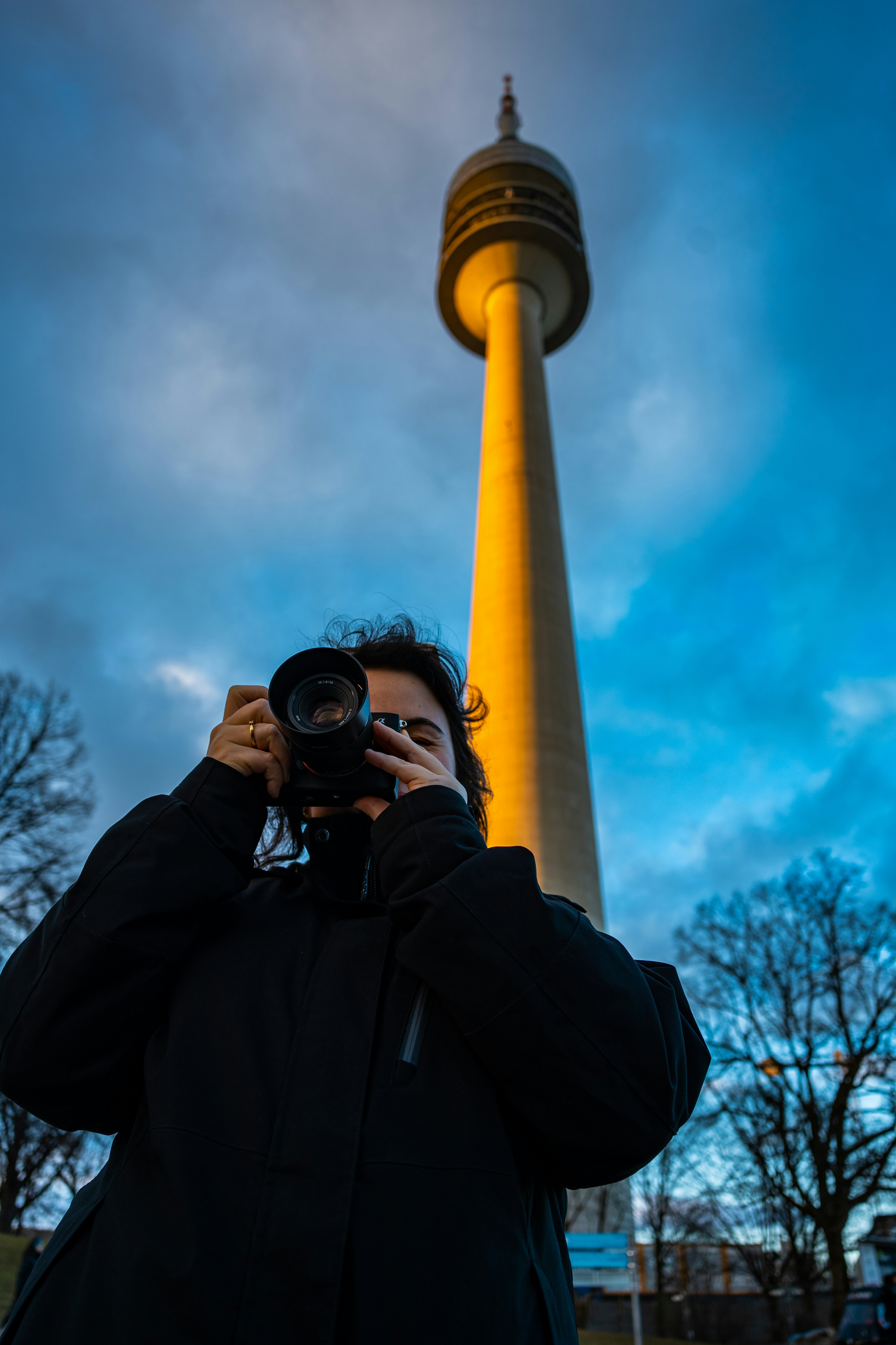 Traveler with a camera framed by a towering city antenna