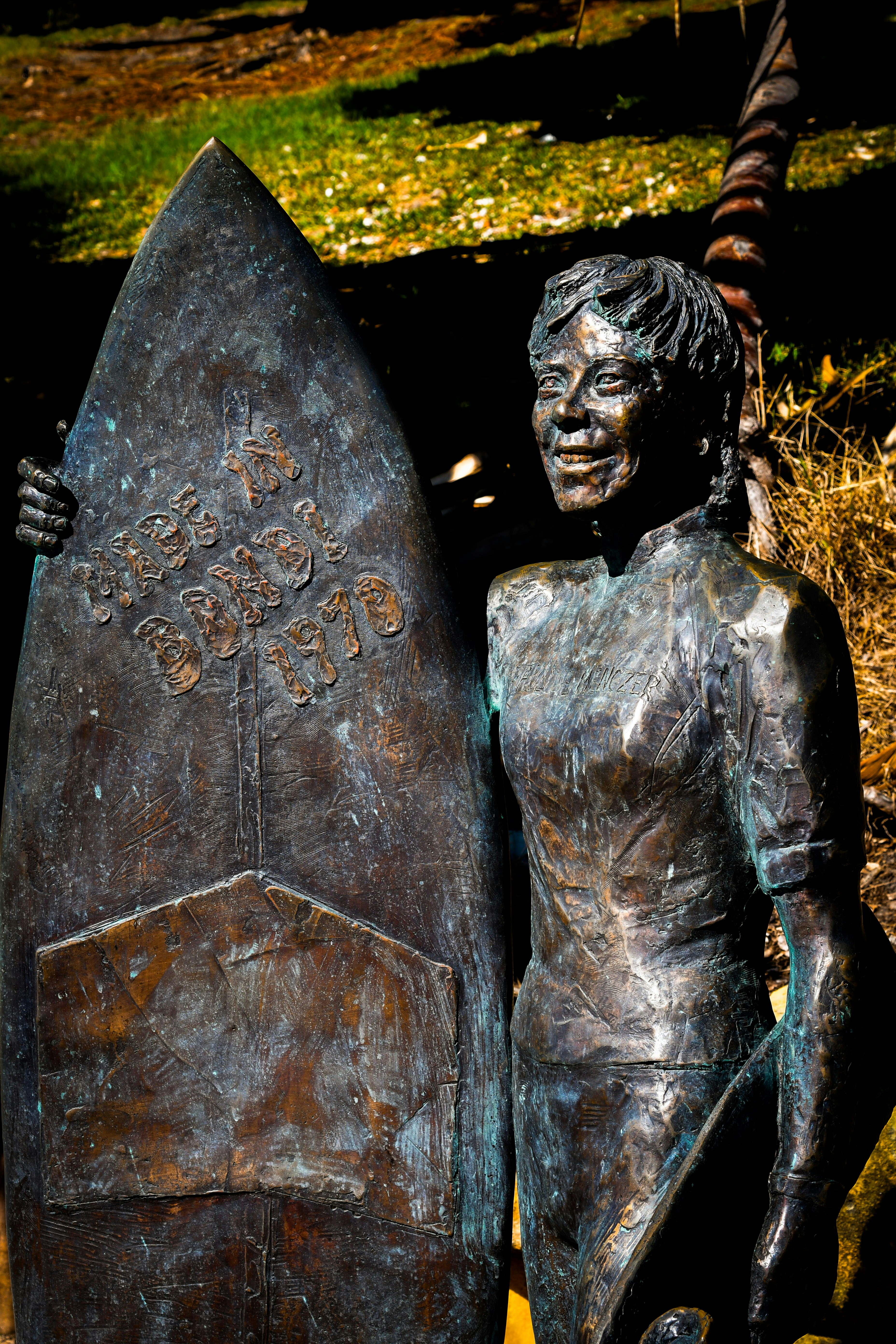 Surfboard Guardian: A Bronze Surfer Stands Beside Its Wave-carved Memorial