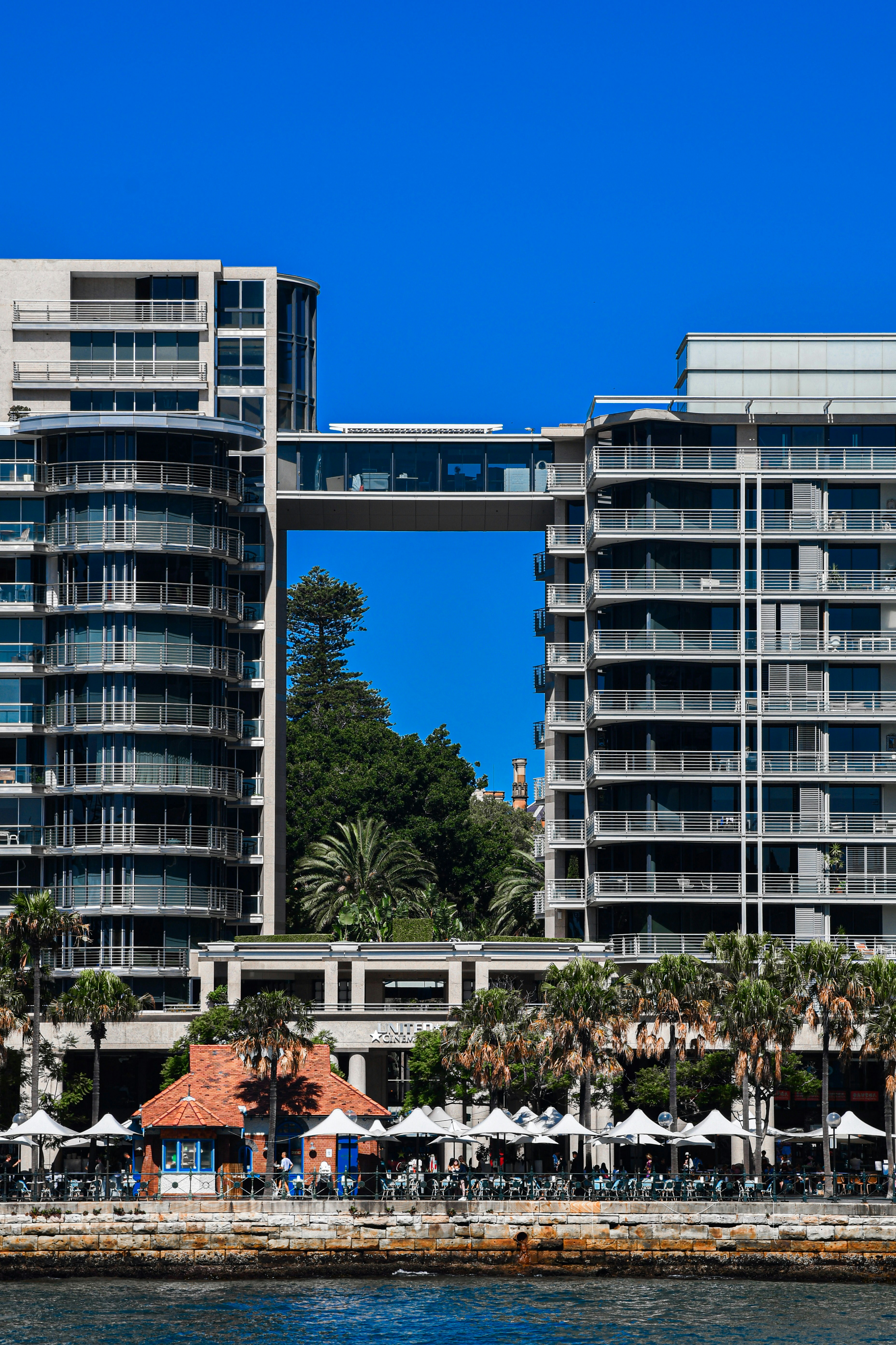 Bridge-Linked Glass Towers Framing a Blue Harbor Sky