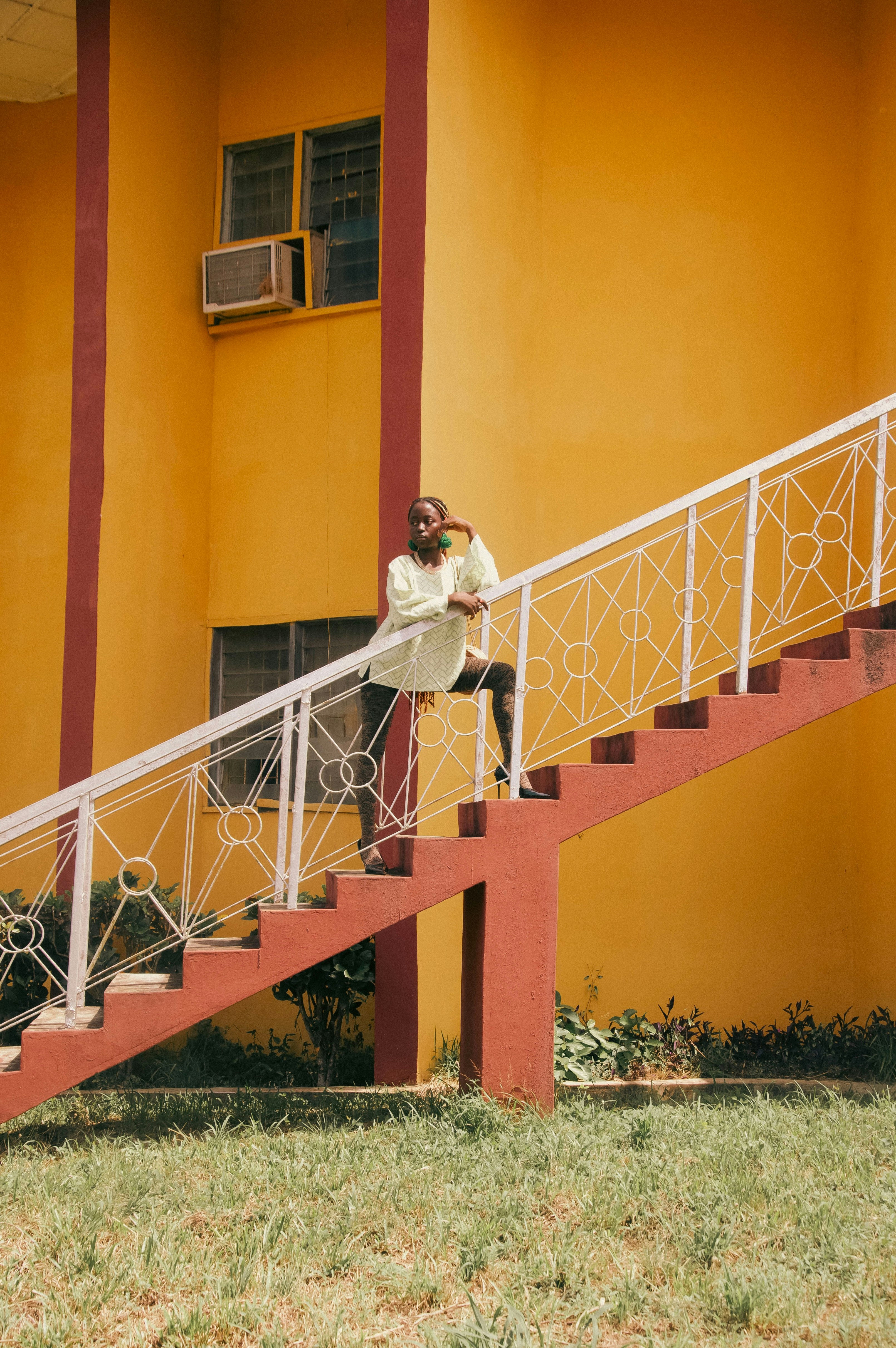Stairway Solitude: A figure pauses mid- ascent against a sunlit yellow-walled facade