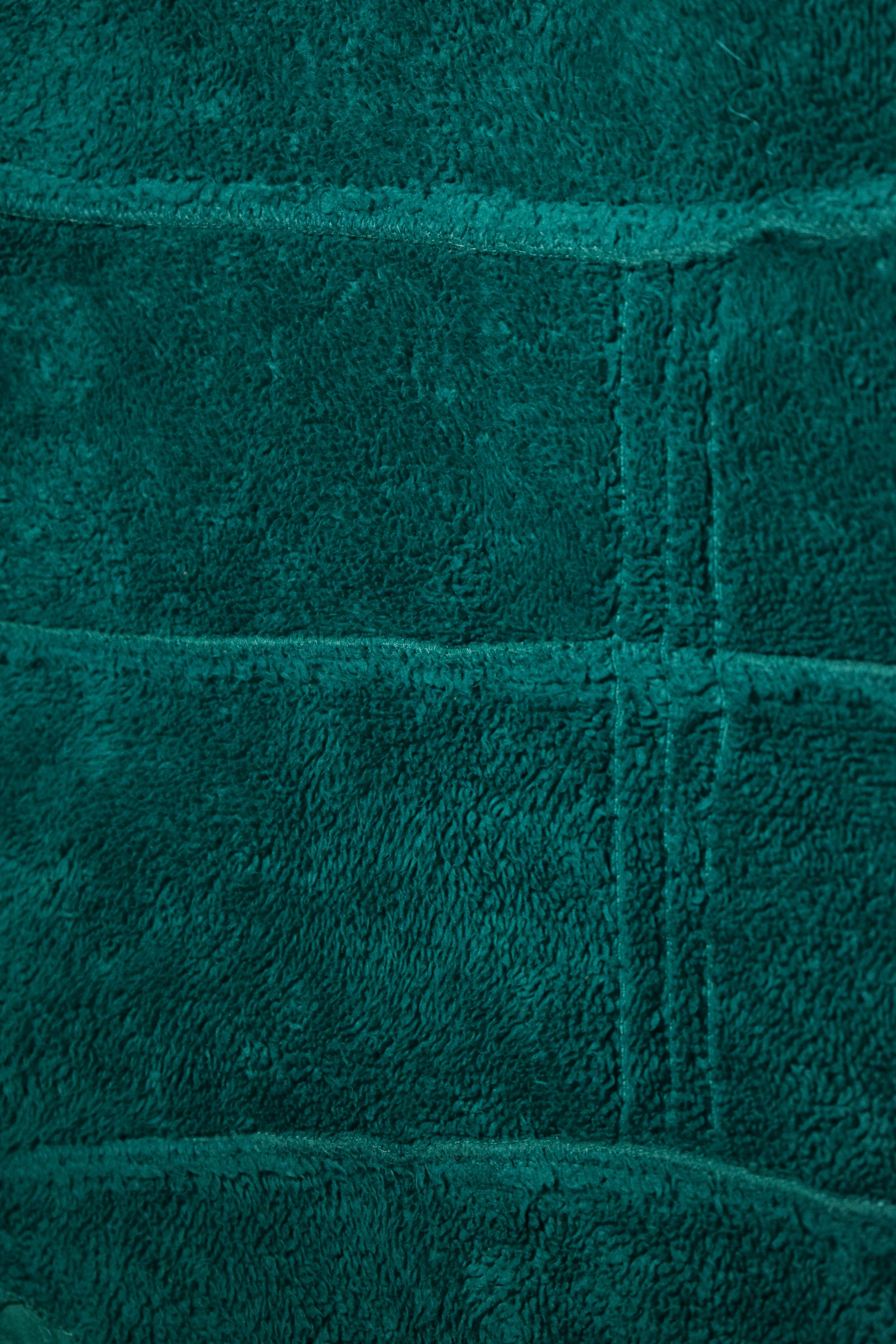 Teal velvet fabric close-up showing stitched seam lines and soft pile. A textile detail image with no people or logo, focusing on surface texture and color.