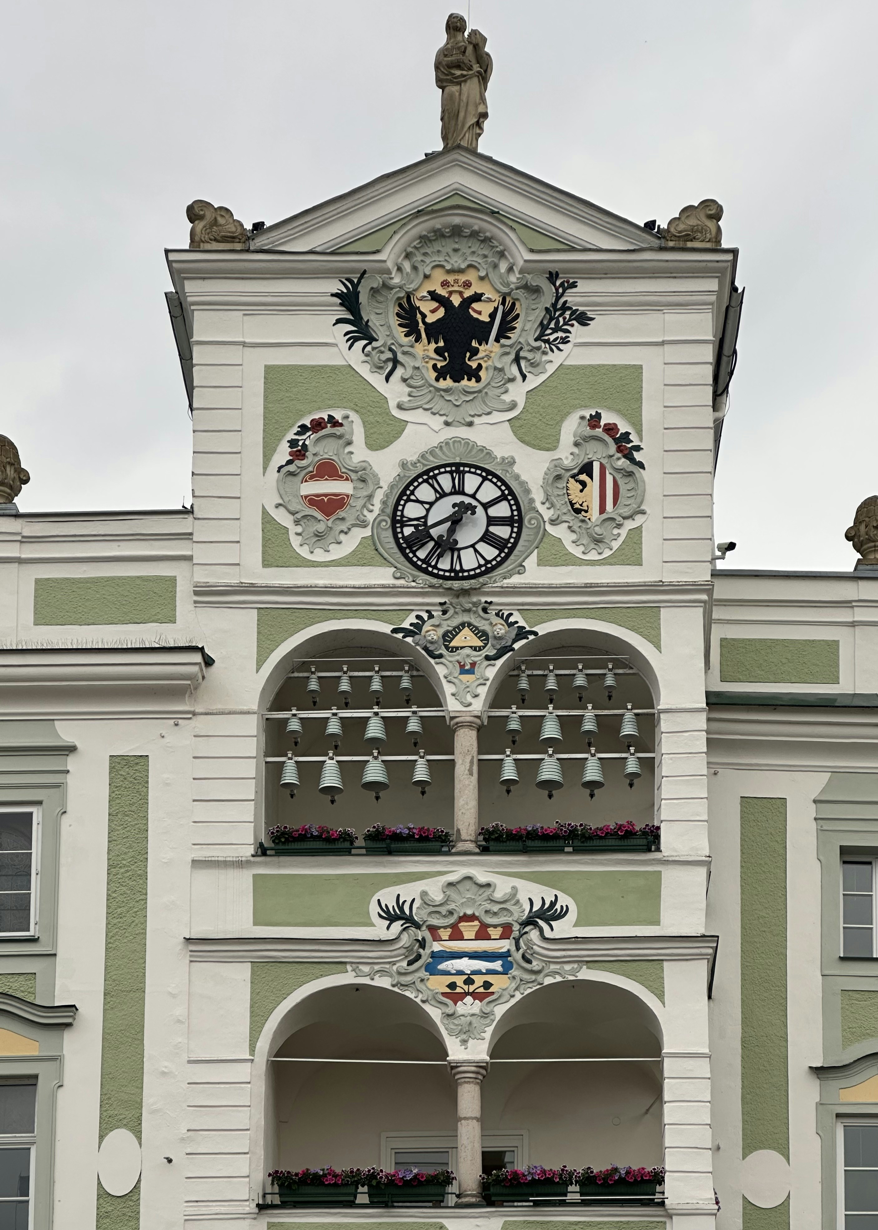 Ornate Clock Tower Silhouette Above Floral Balconies