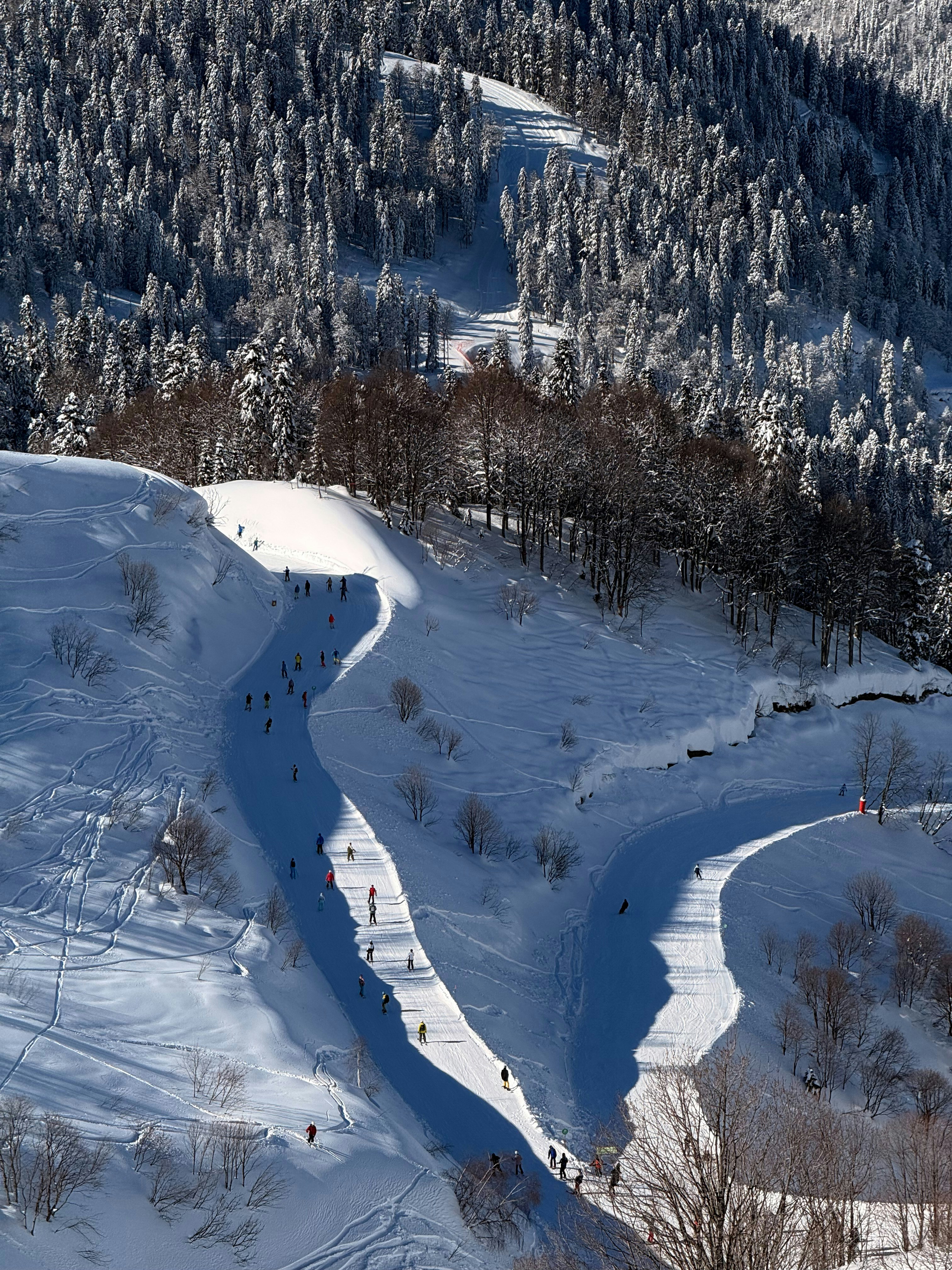 Snowbound switchback: a ribbon of skiers carving through a frosted valley