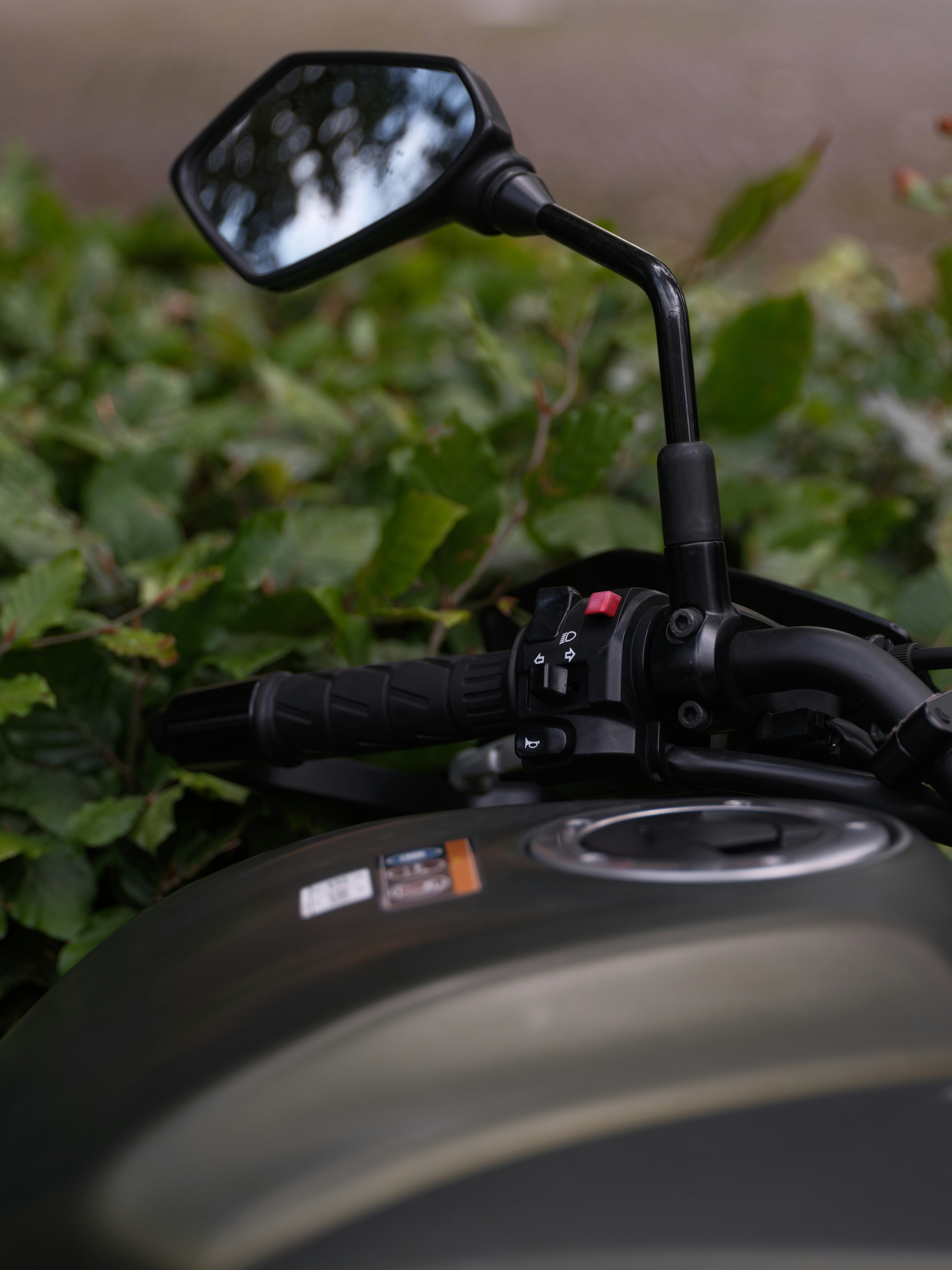 Mirror in the Mist: A Close-Up of a Motorbike Handlebar and Rear-View Mirror