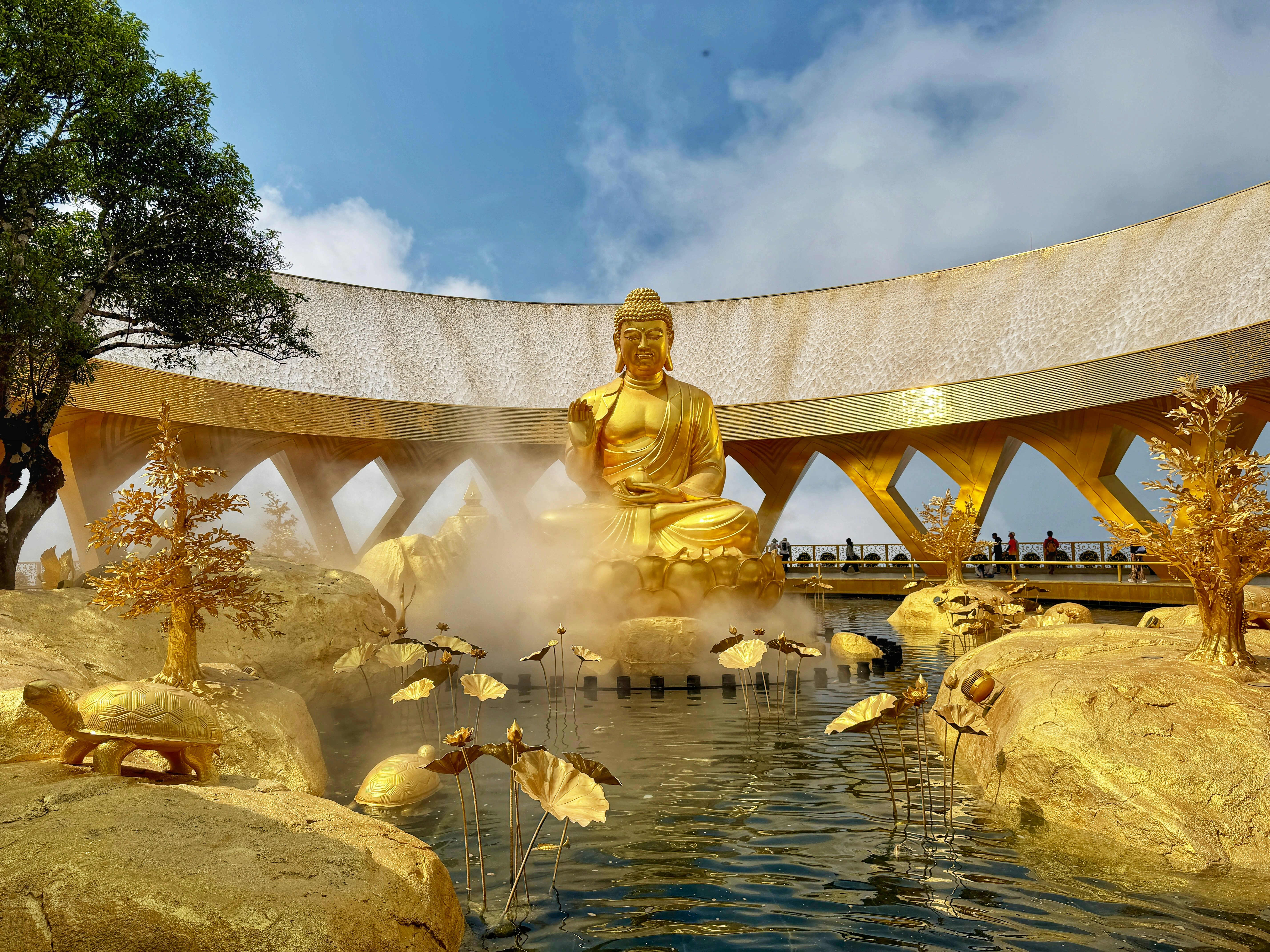 Golden Statue Overlooking a Misty Pond at a Scenic Buddhist Dome