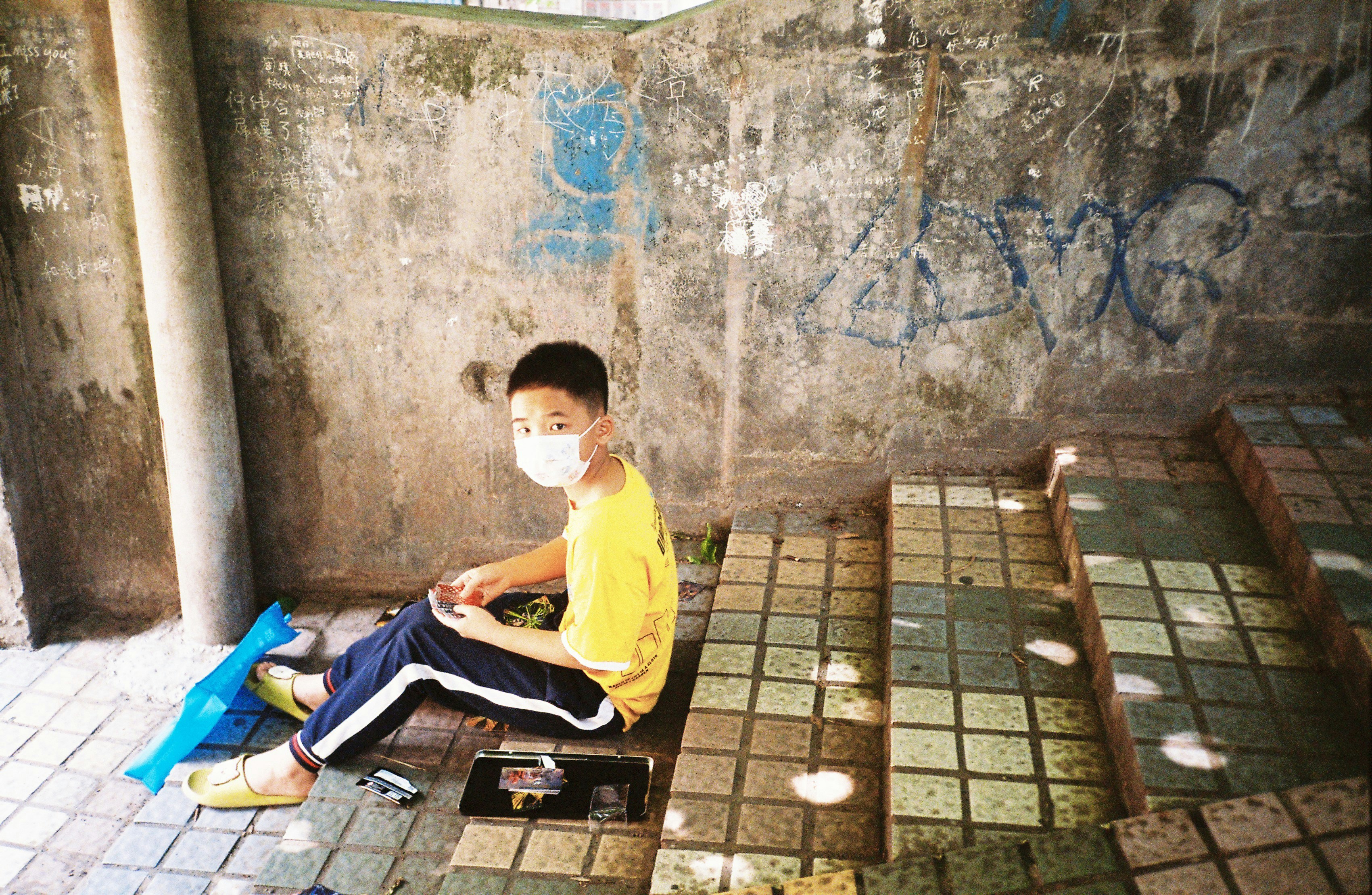 Mask and Mosaic: A Quiet Moment by the Graffitied Wall