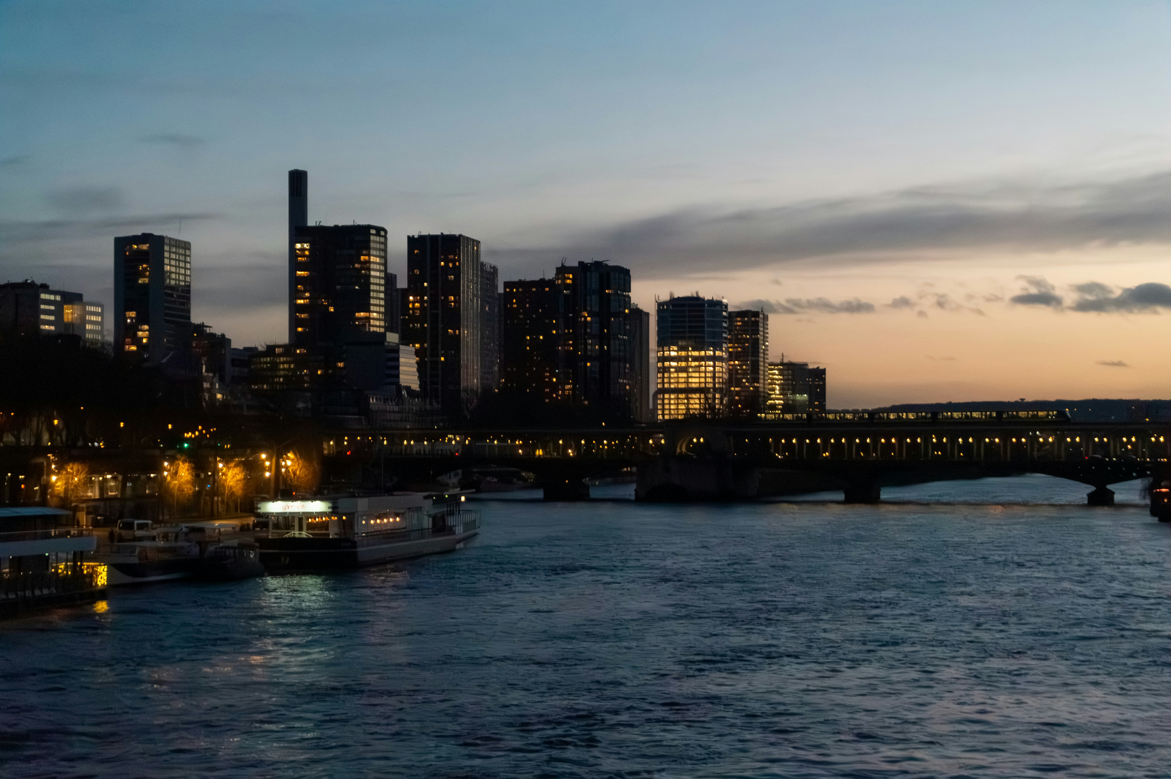 Urban Dusk Over the River: City Lights Glow on Calm Waters
