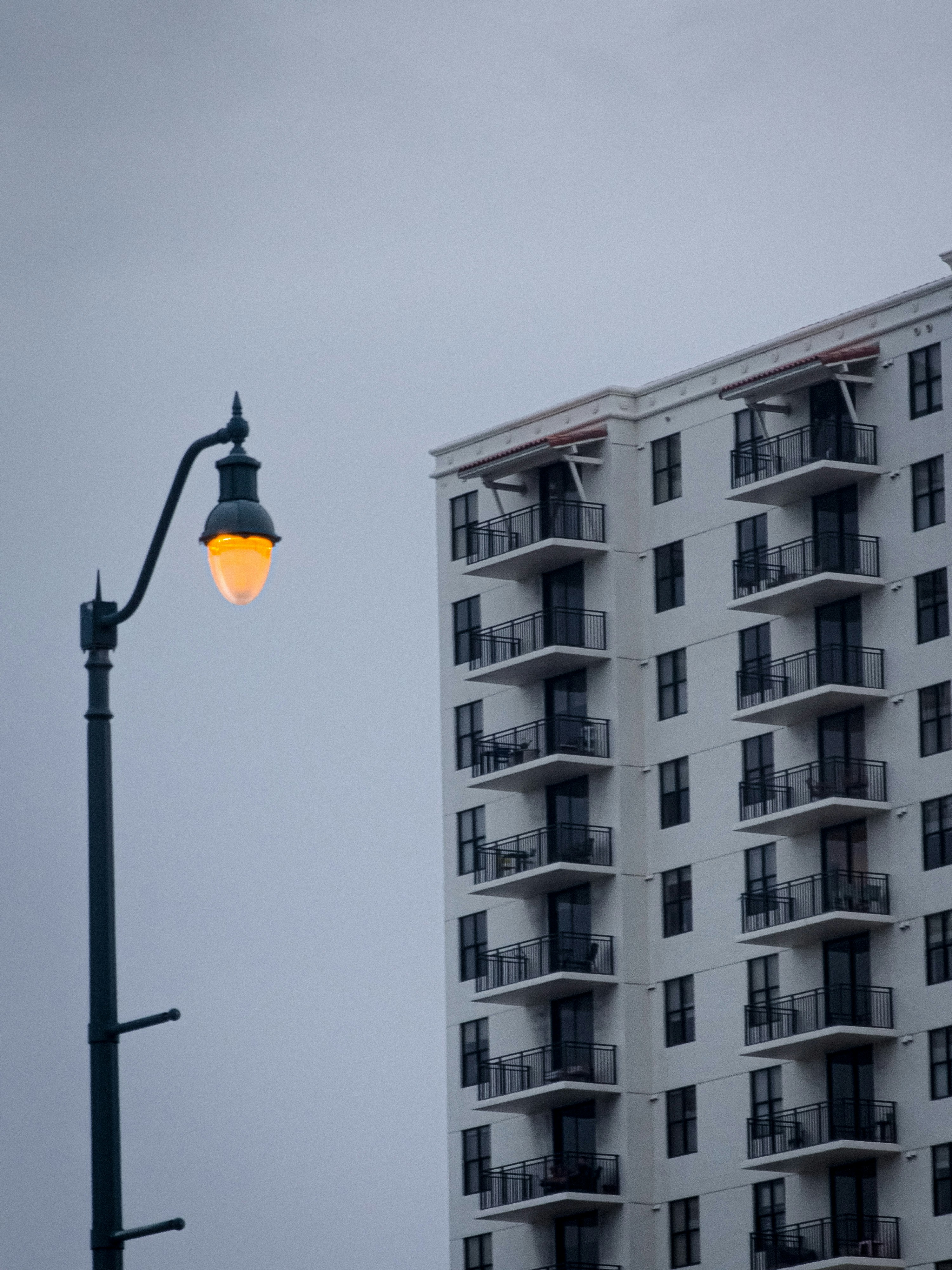 Streetlamp and Modern Flats: Evening Glow Beside a Towering Windowed Facade