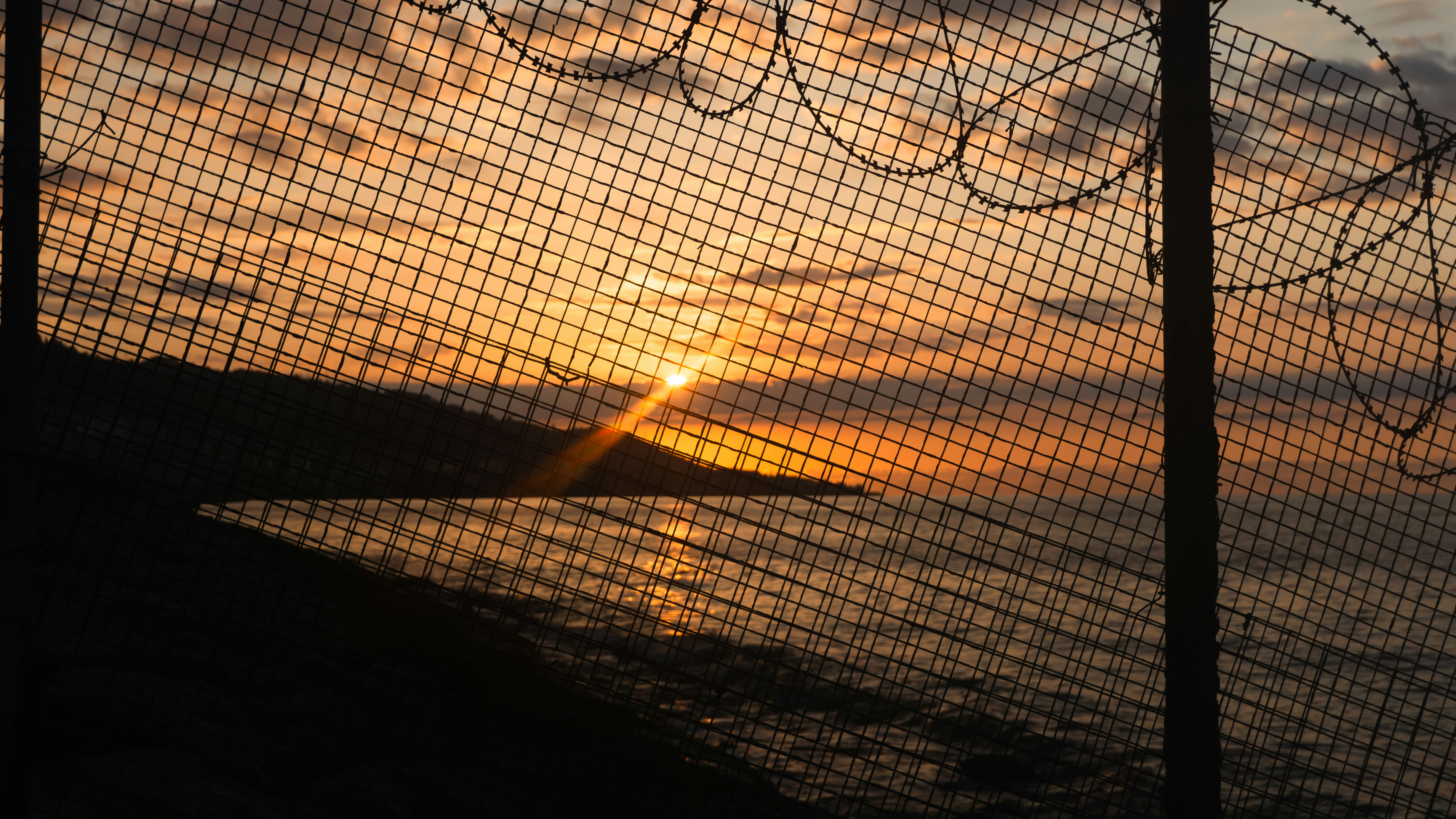 Sunlit Fence: Sunset Over a Netted Barrier