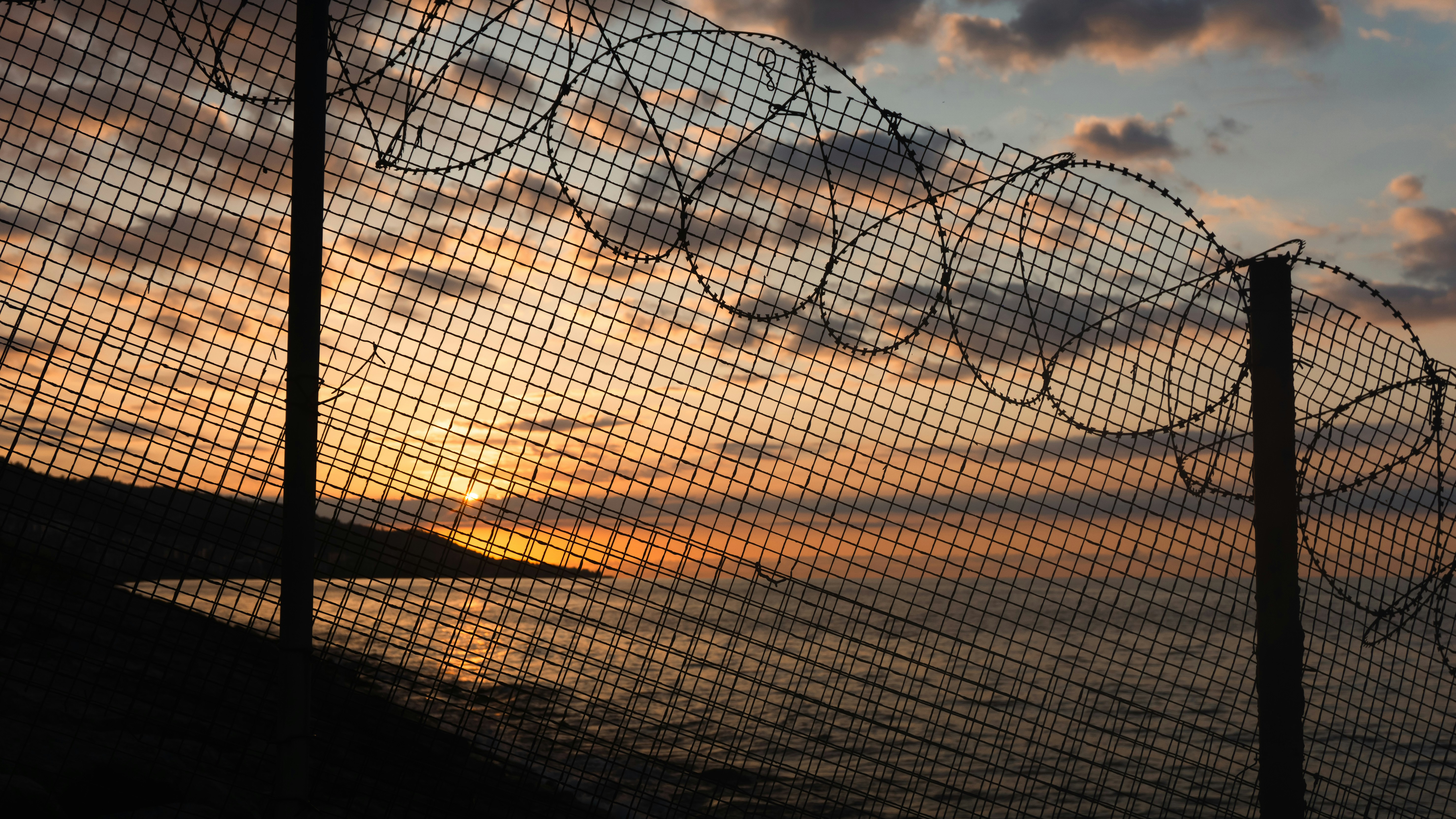 Sunset Over Razorwire: Dusk Over the Shoreline