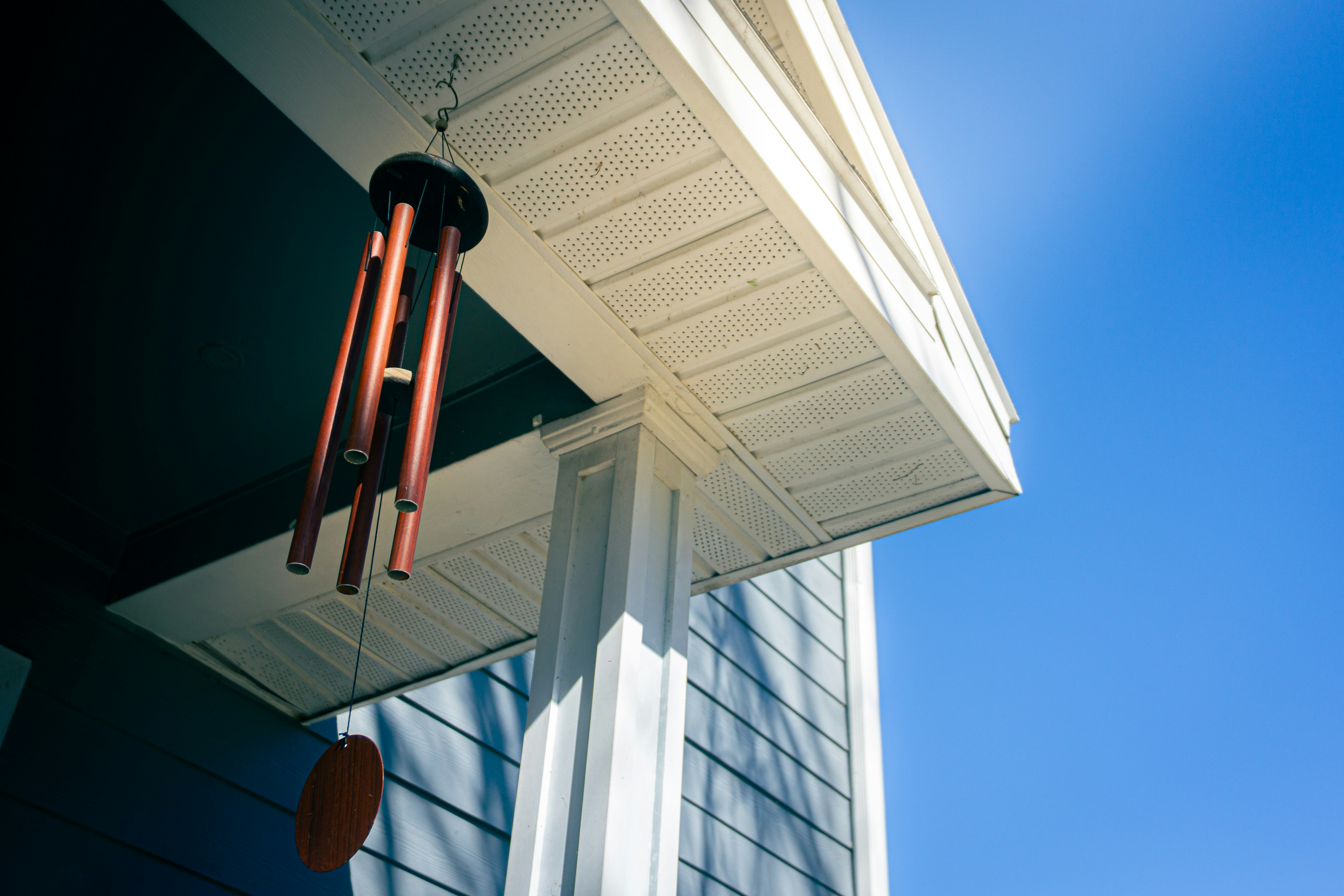 Wind Chime on a Sunlit Porch Framed by a Bright Blue Sky