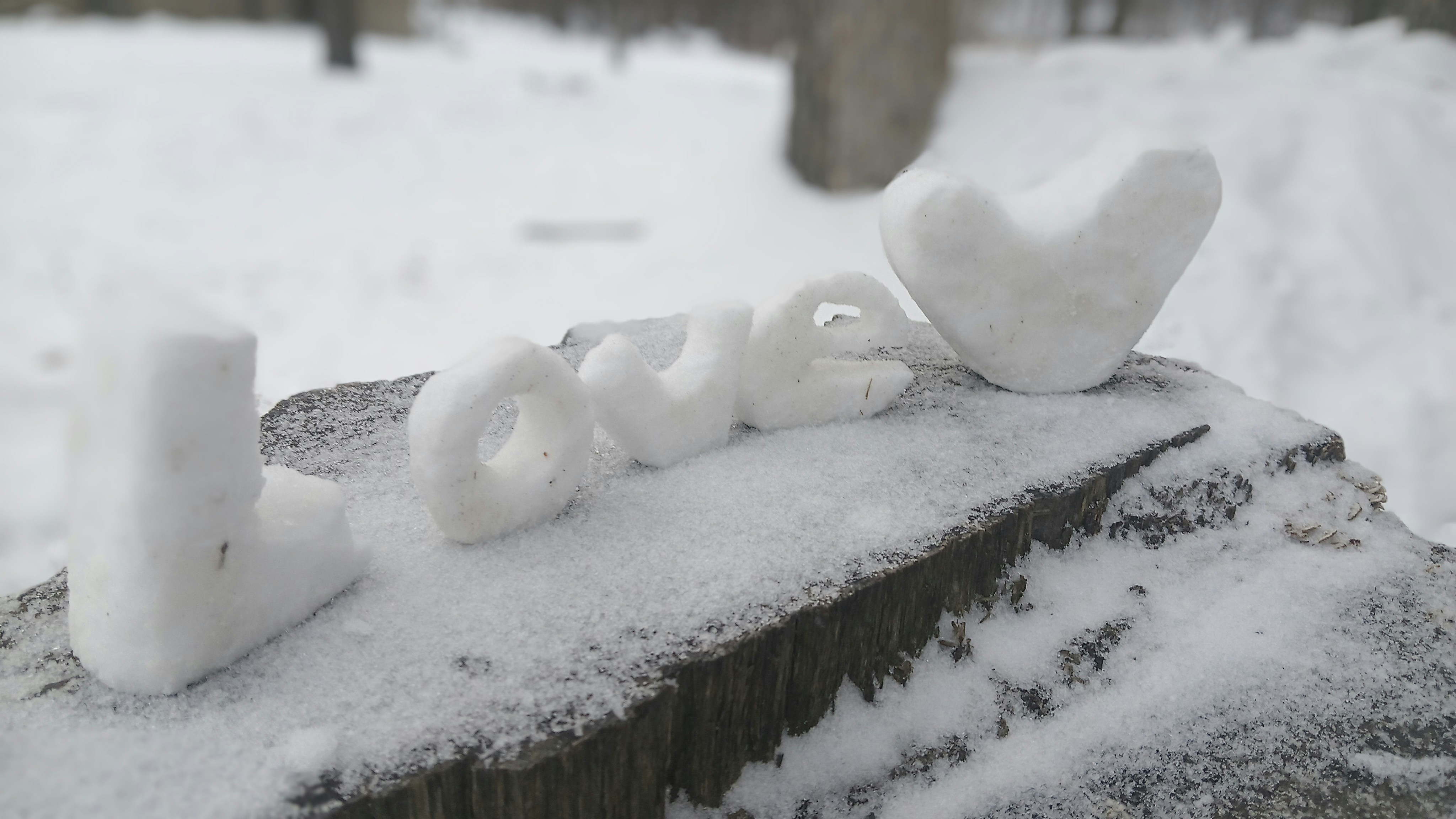 Snowy letters spell out 'love' on a wooden surface