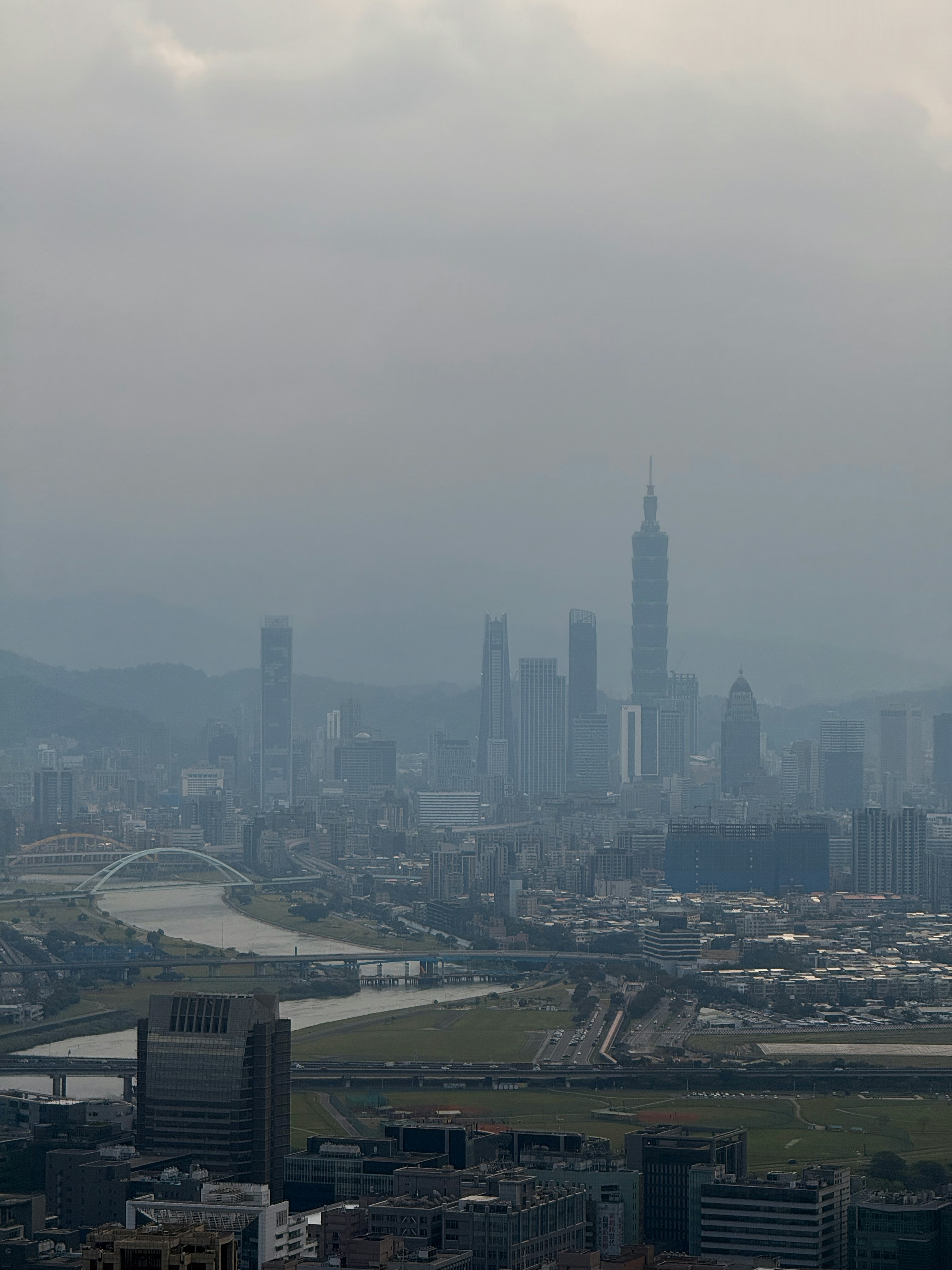 Skyline in the Mist: Taipei’s Towering Silhouette Above the River