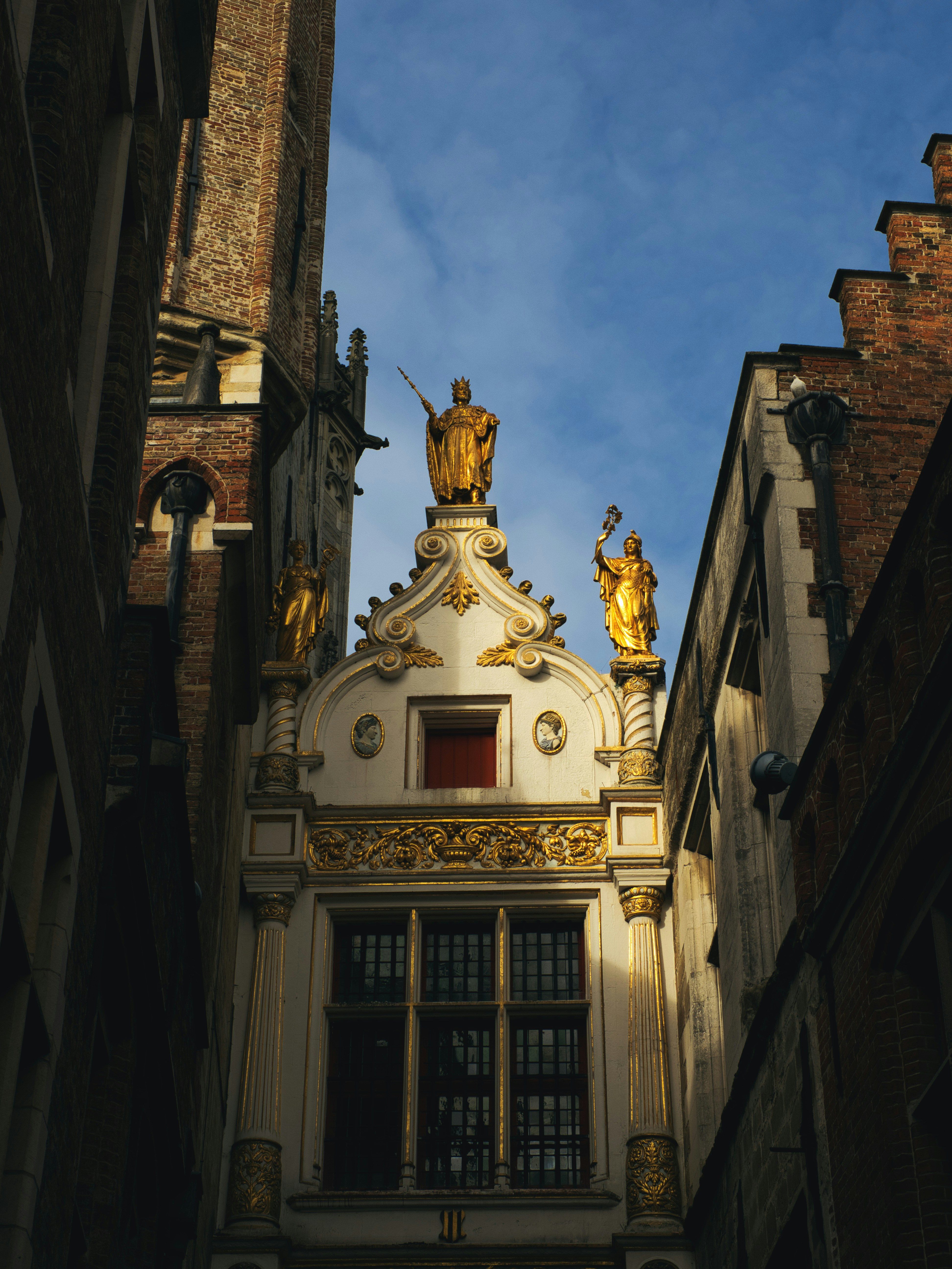 Golden Statues Crown a Baroque Facade Between Brick Wings
