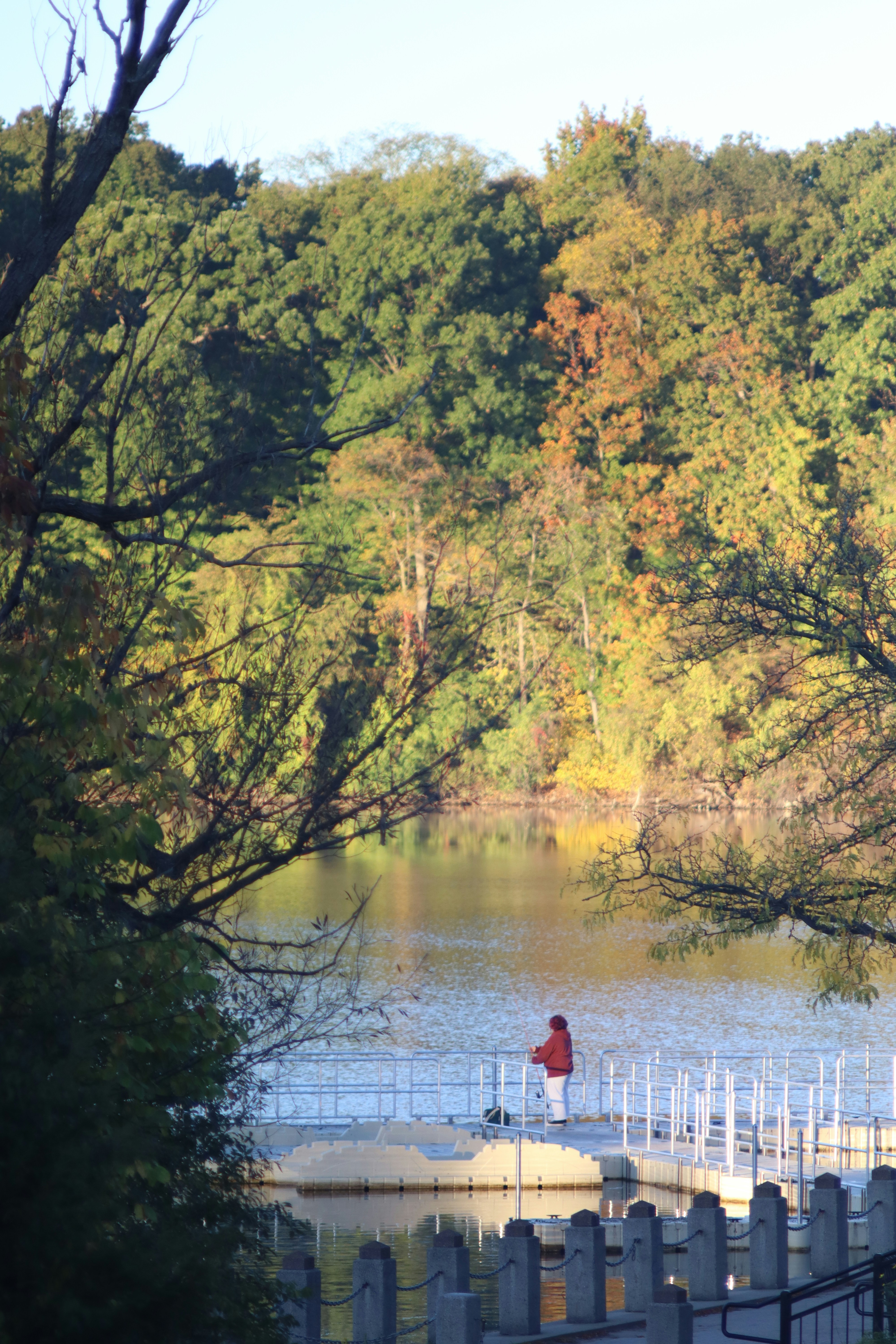 Red-clad angler at the edge of a sunlit autumn lake