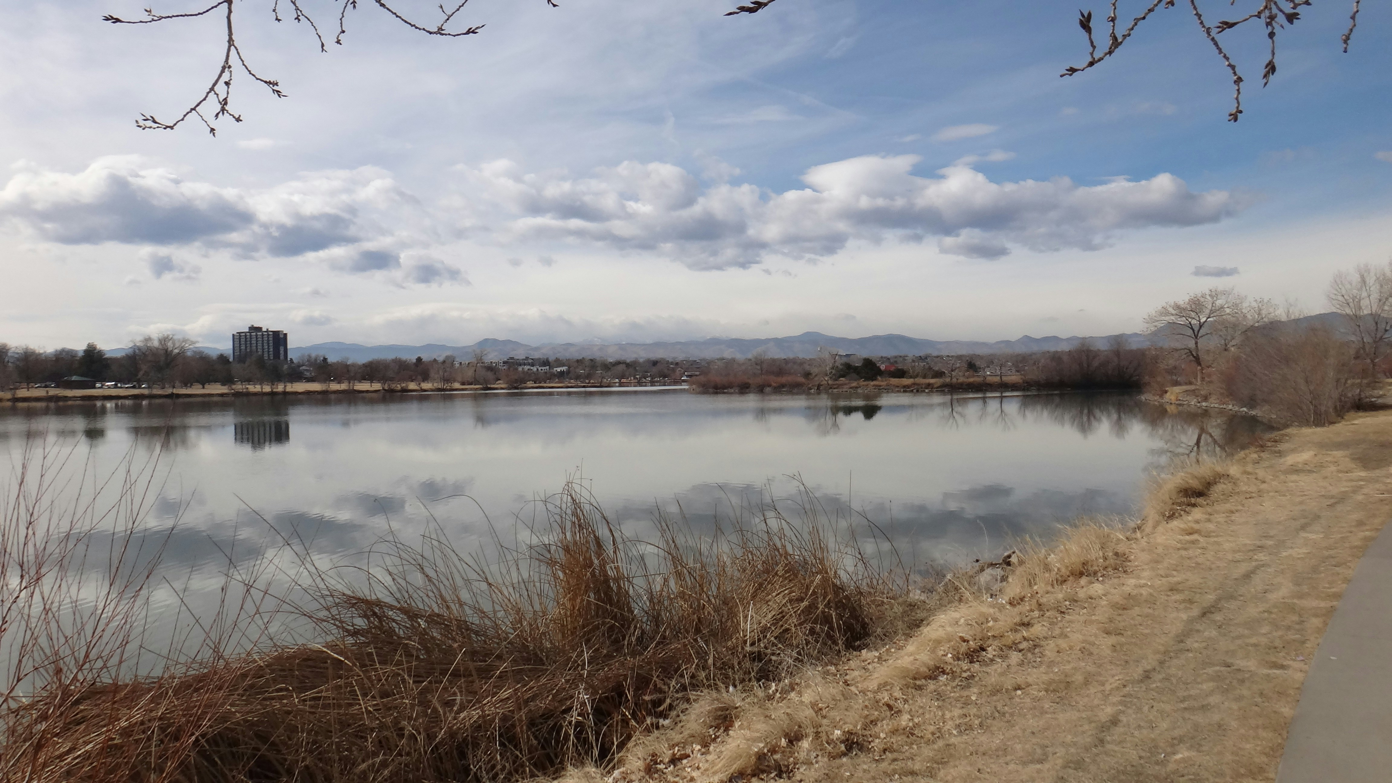 Calm lake reflects clouds and distant mountains under sky