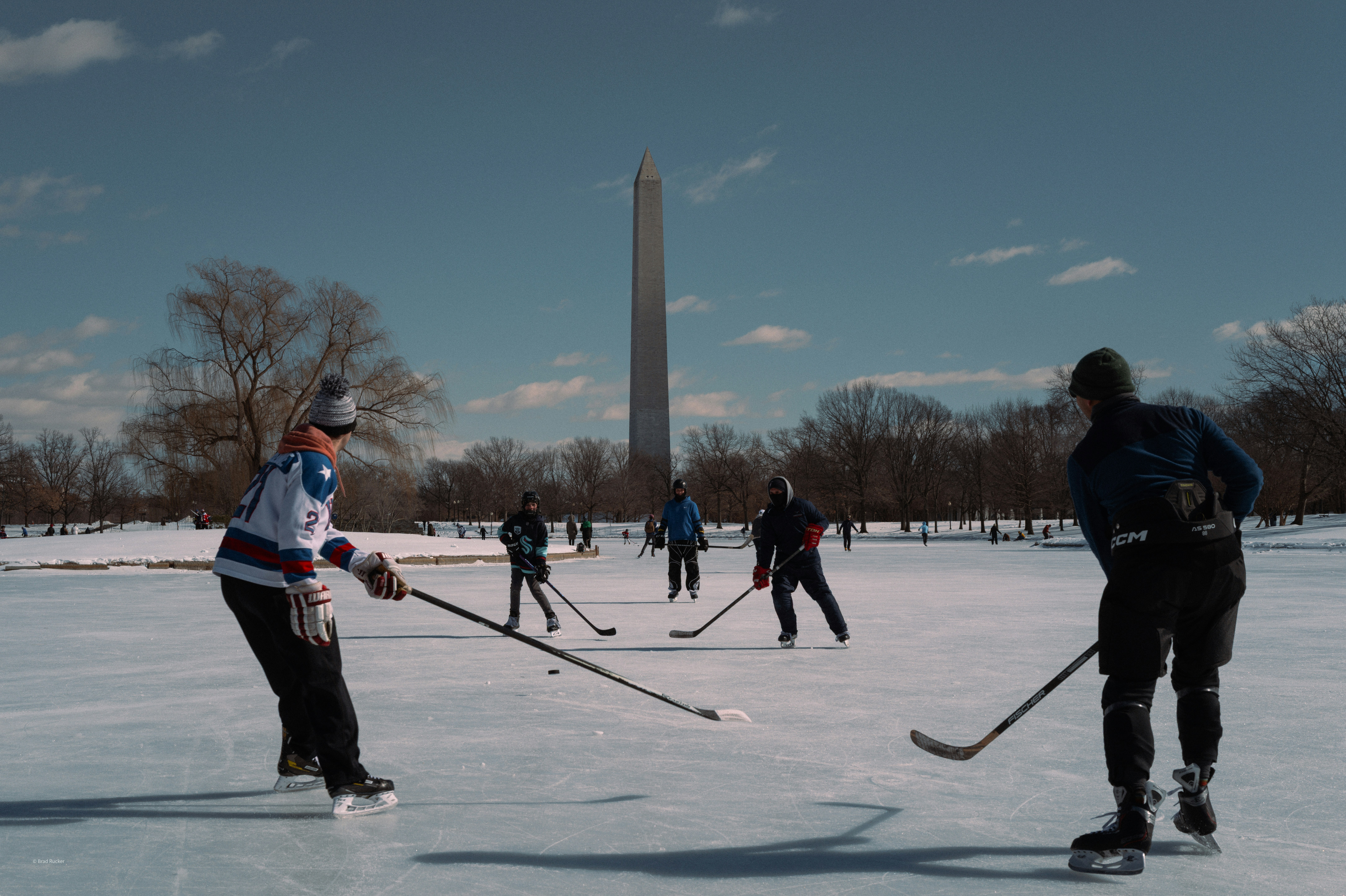 Skaters Span the Ice with the Washington Monument Under a Clear Sky
