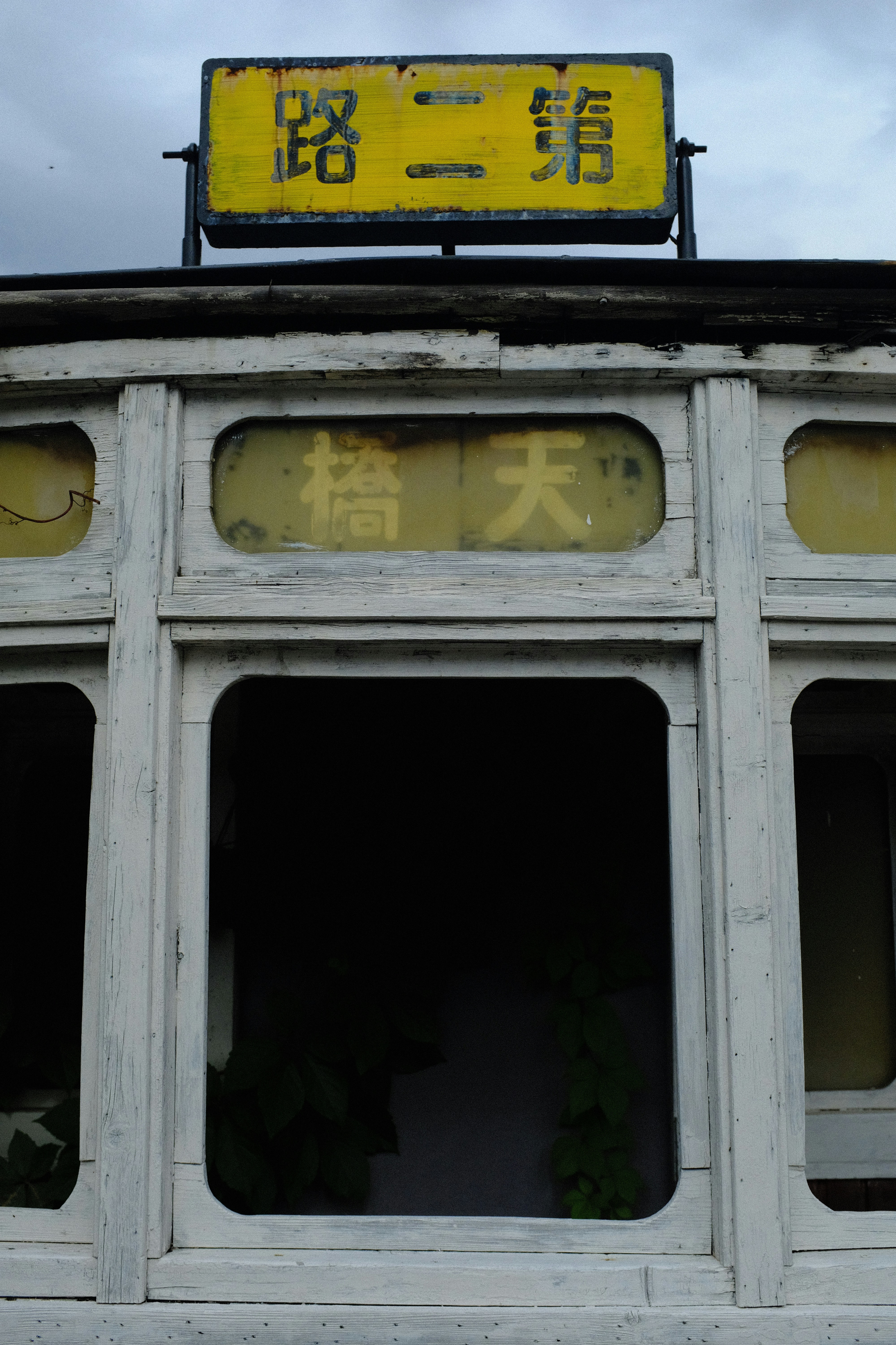 Weathered Yellow Sign Above a Dilapidated Carriage Window