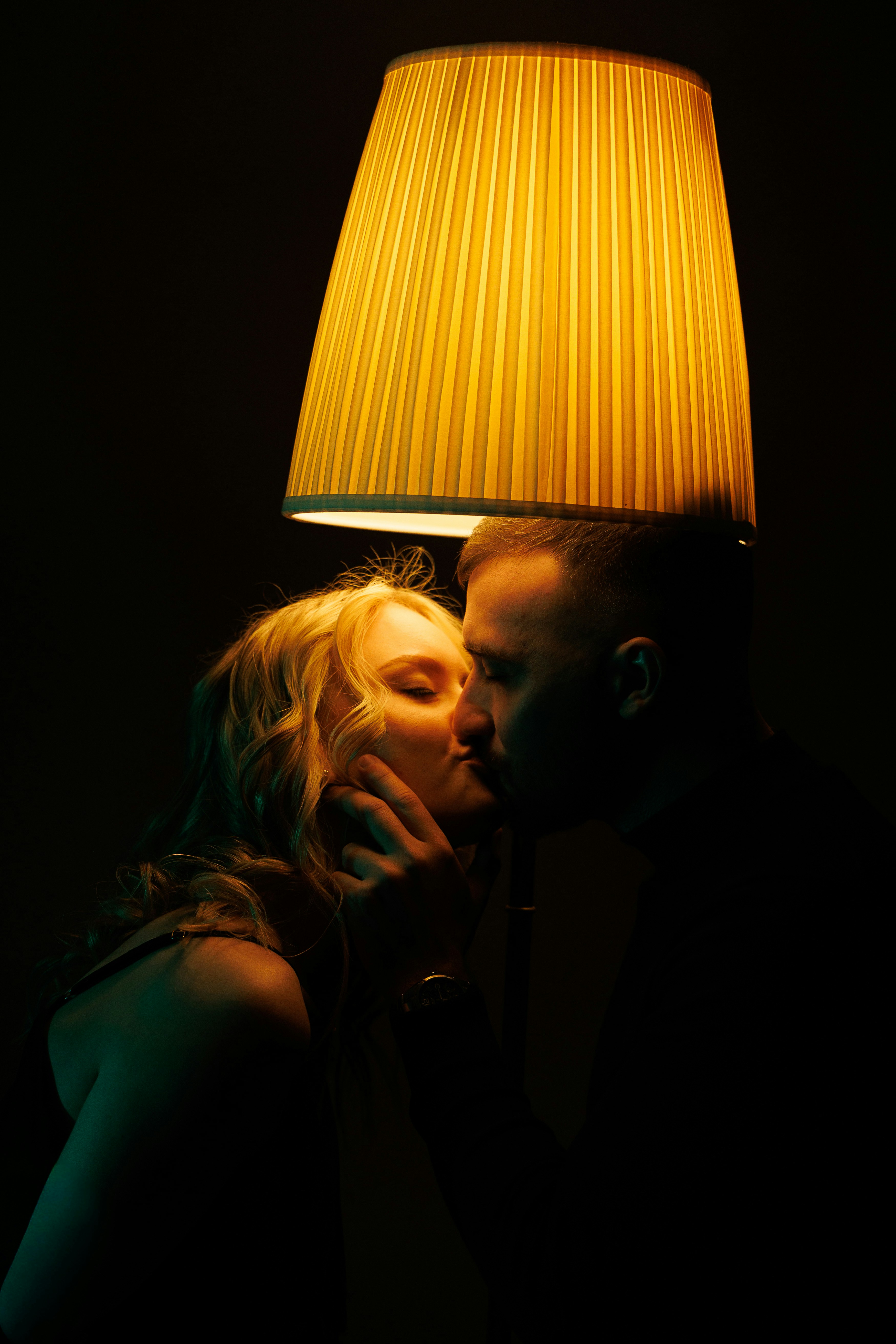 Under the Golden Lamp: Intimate Kiss in a Dim Studio