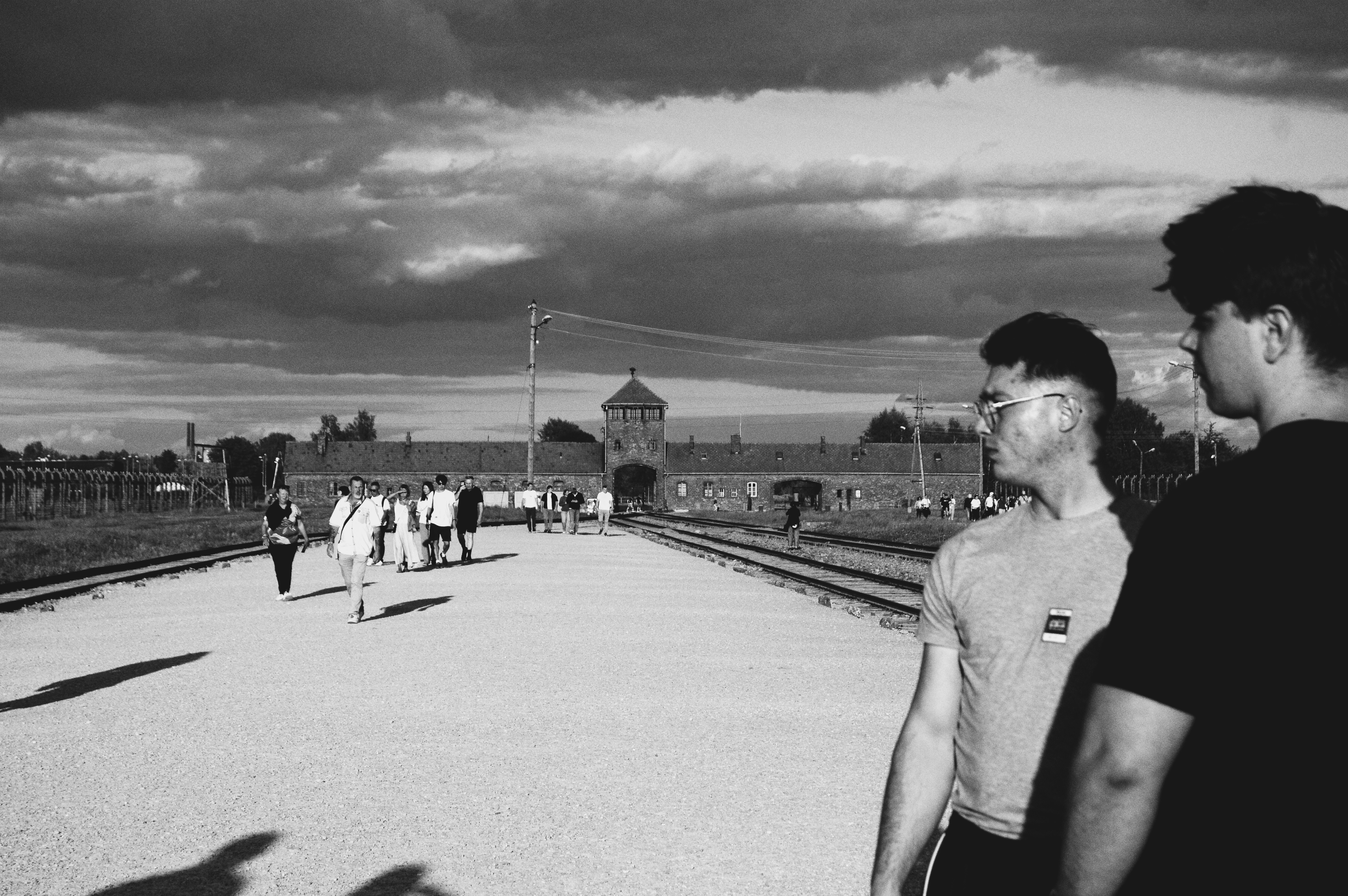 At the Platform Edge: Two Figures in the Foreground Watch a Quiet Line of Travelers