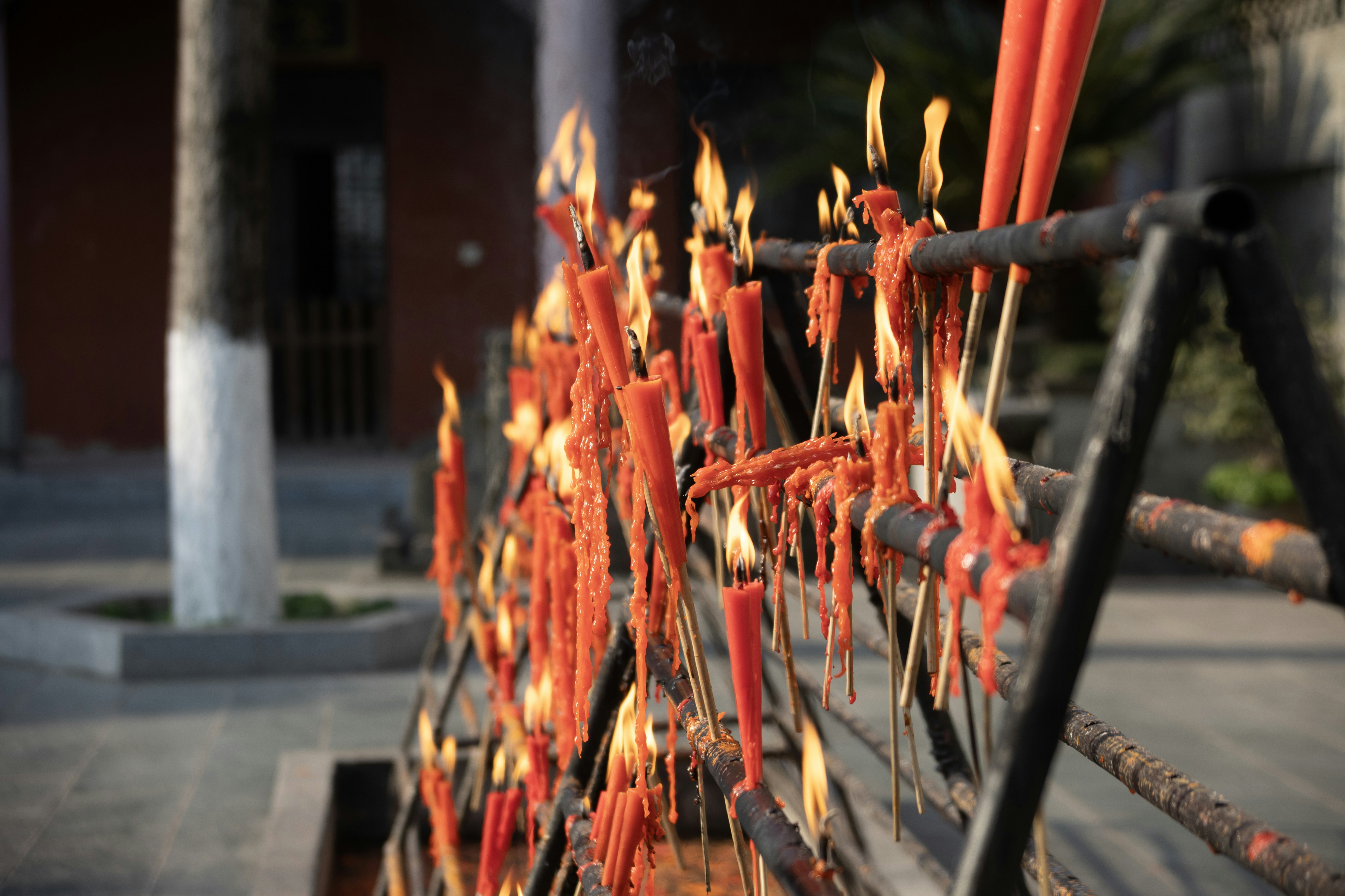 Ritual Candles on a Worn Iron Fence