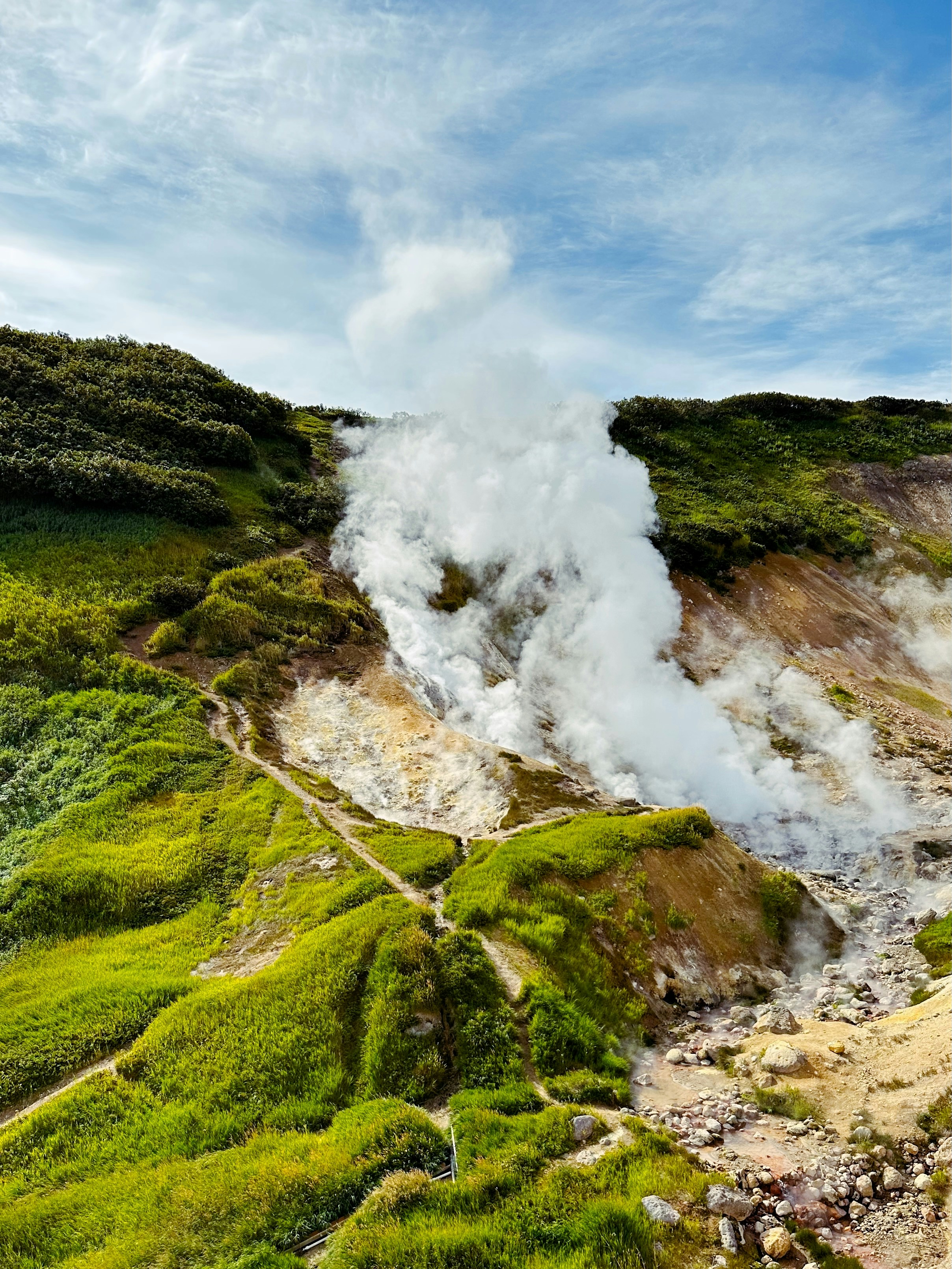 Steam Veil Over Verdant Ridges