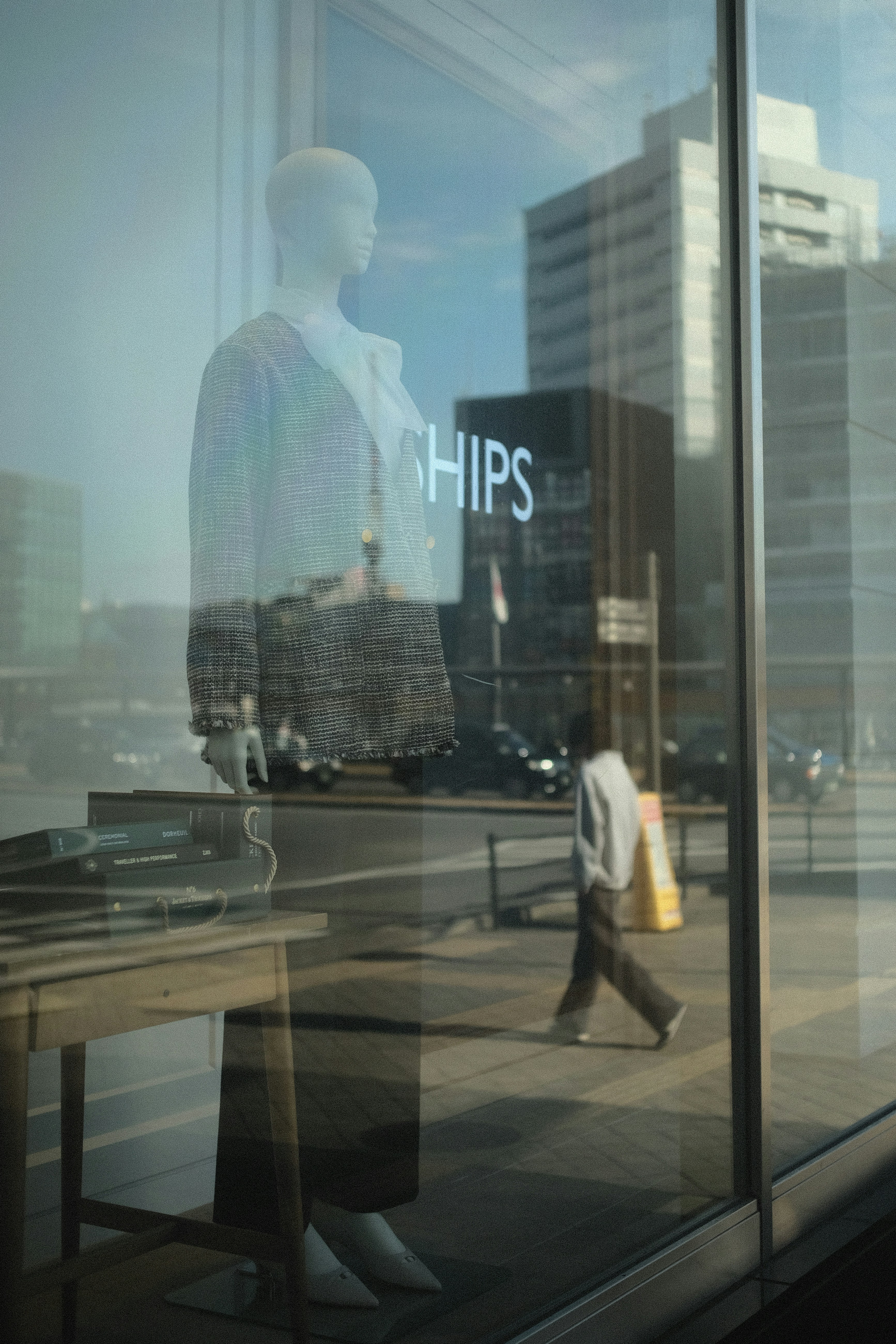 Reflected Fashion: A mannequin in a glass storefront with cityscape in the pane
