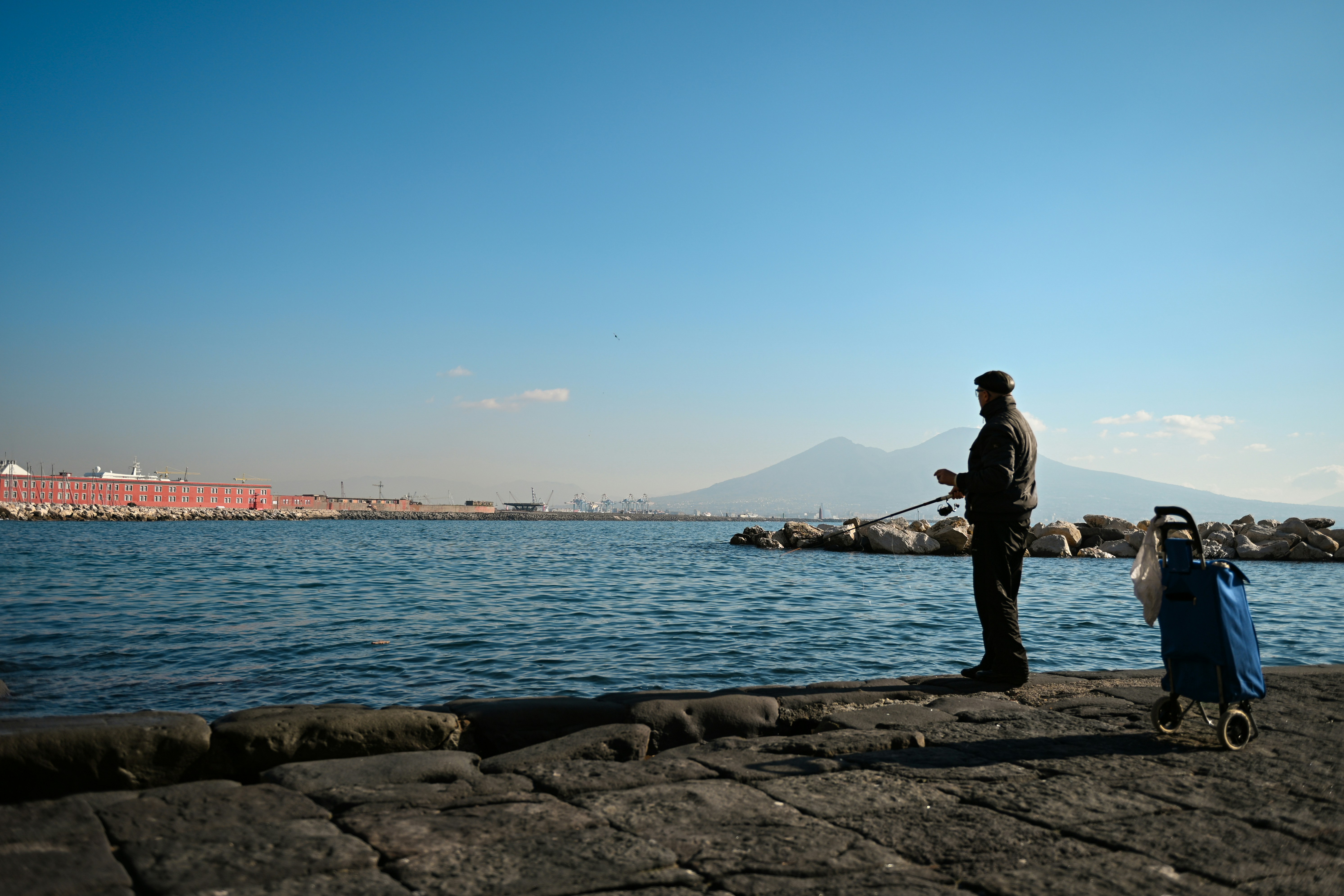 Line by the Sea: A Fisherman and a Rolling Trolley at Dusk