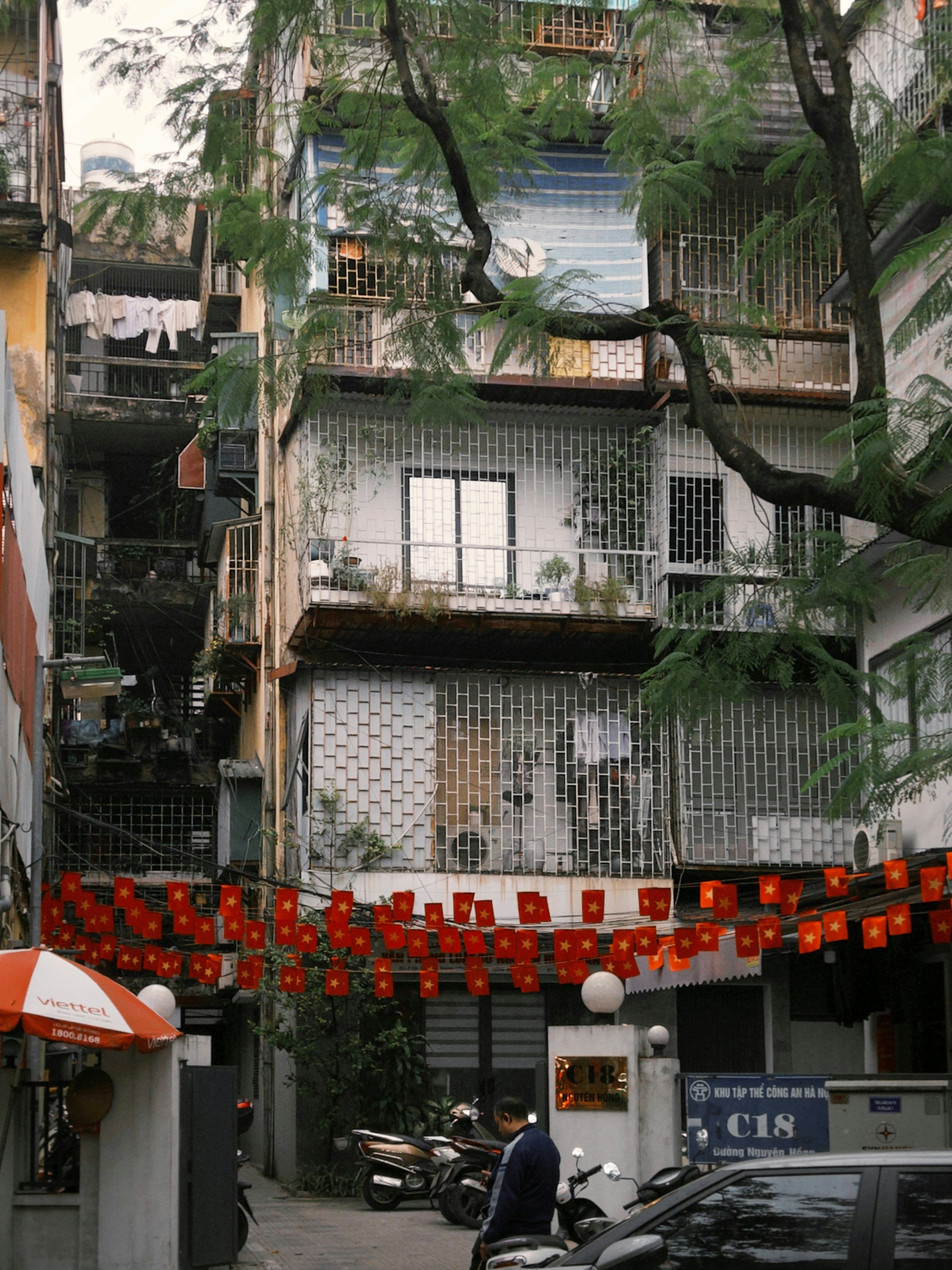 Urban Courtyard Echoes: Red Flags, Distant Rails, and Quiet Activity