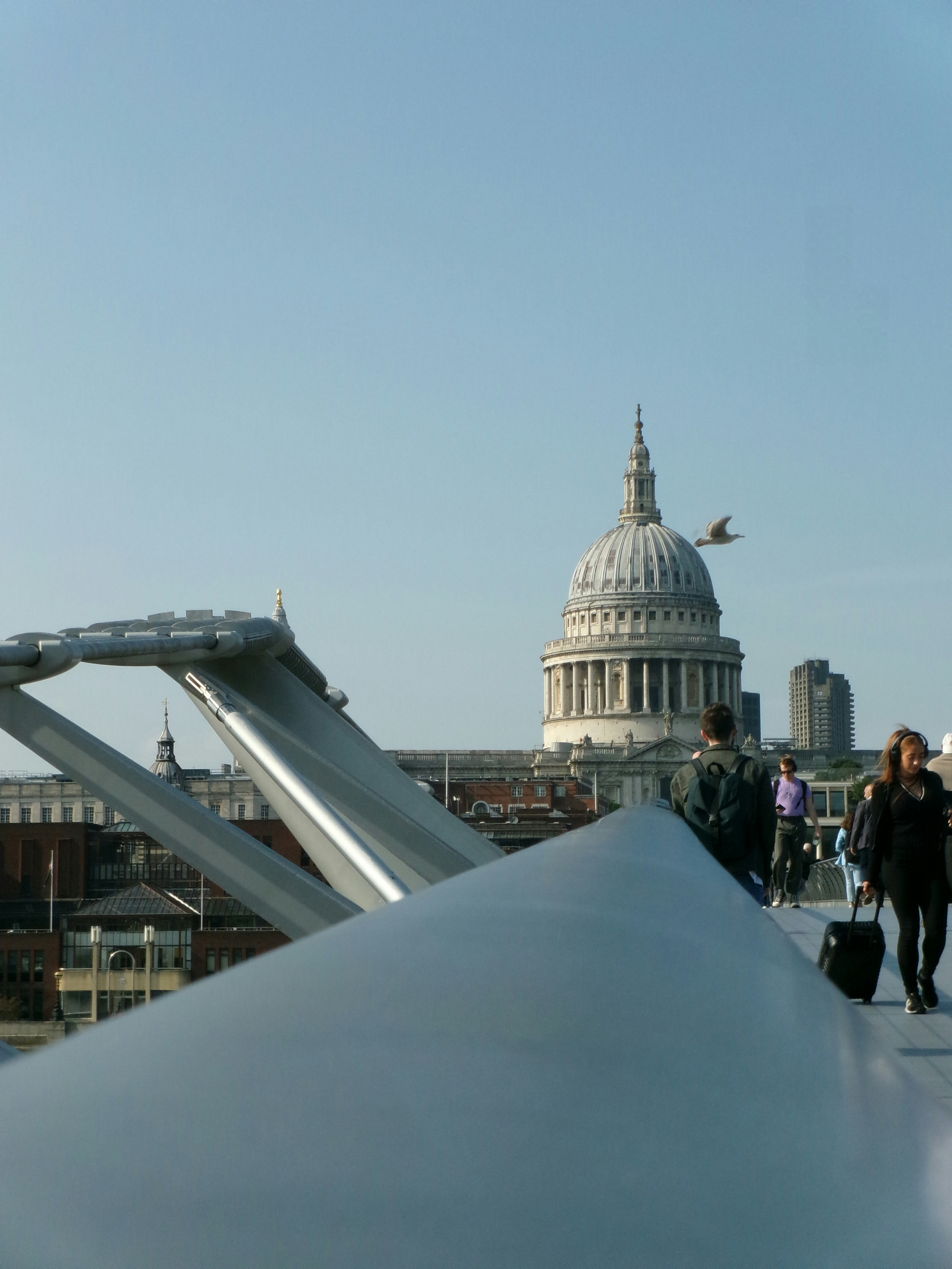 People walk across a bridge towards st. paul's cathedral.