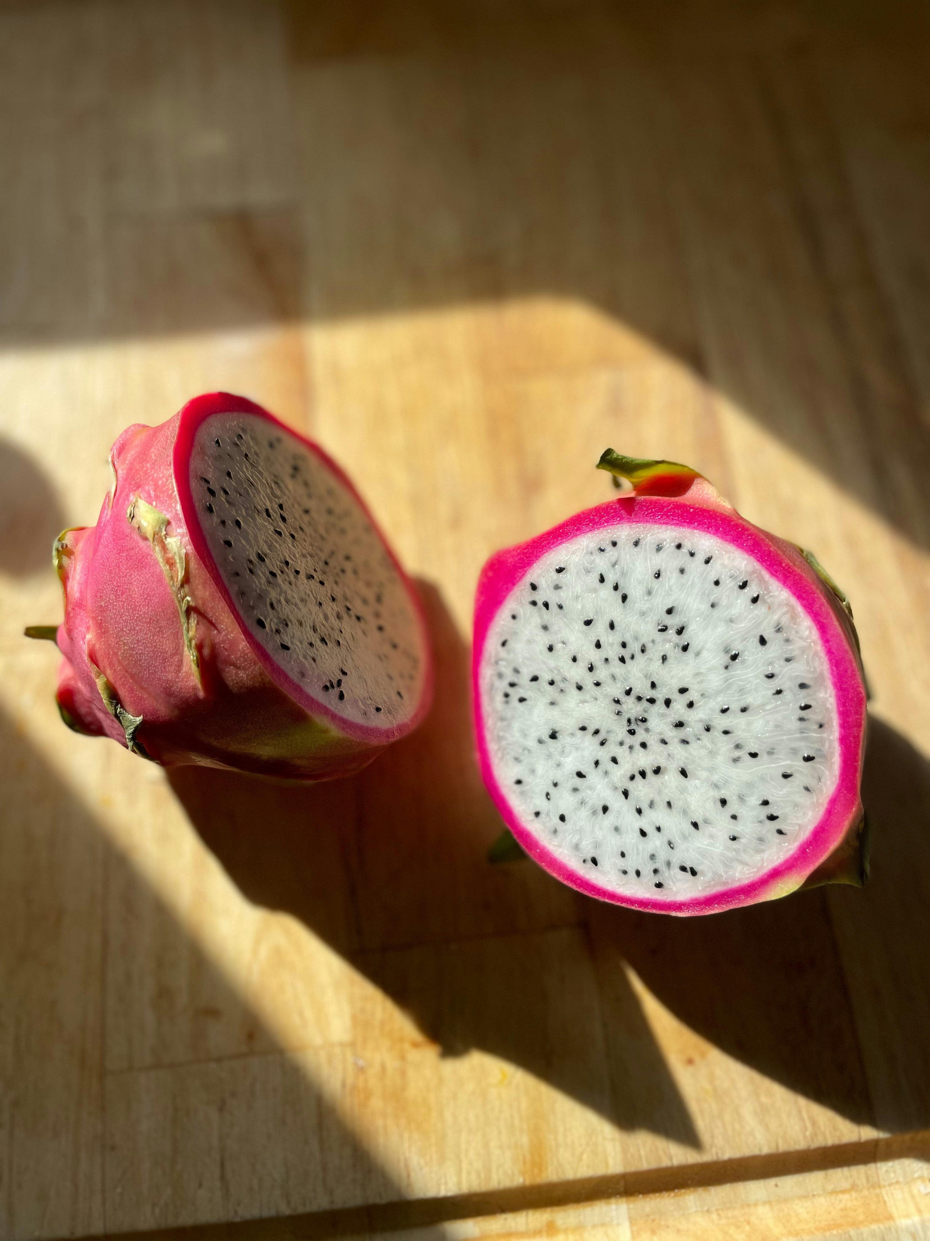 Dragon fruit halves on sunlit wooden surface