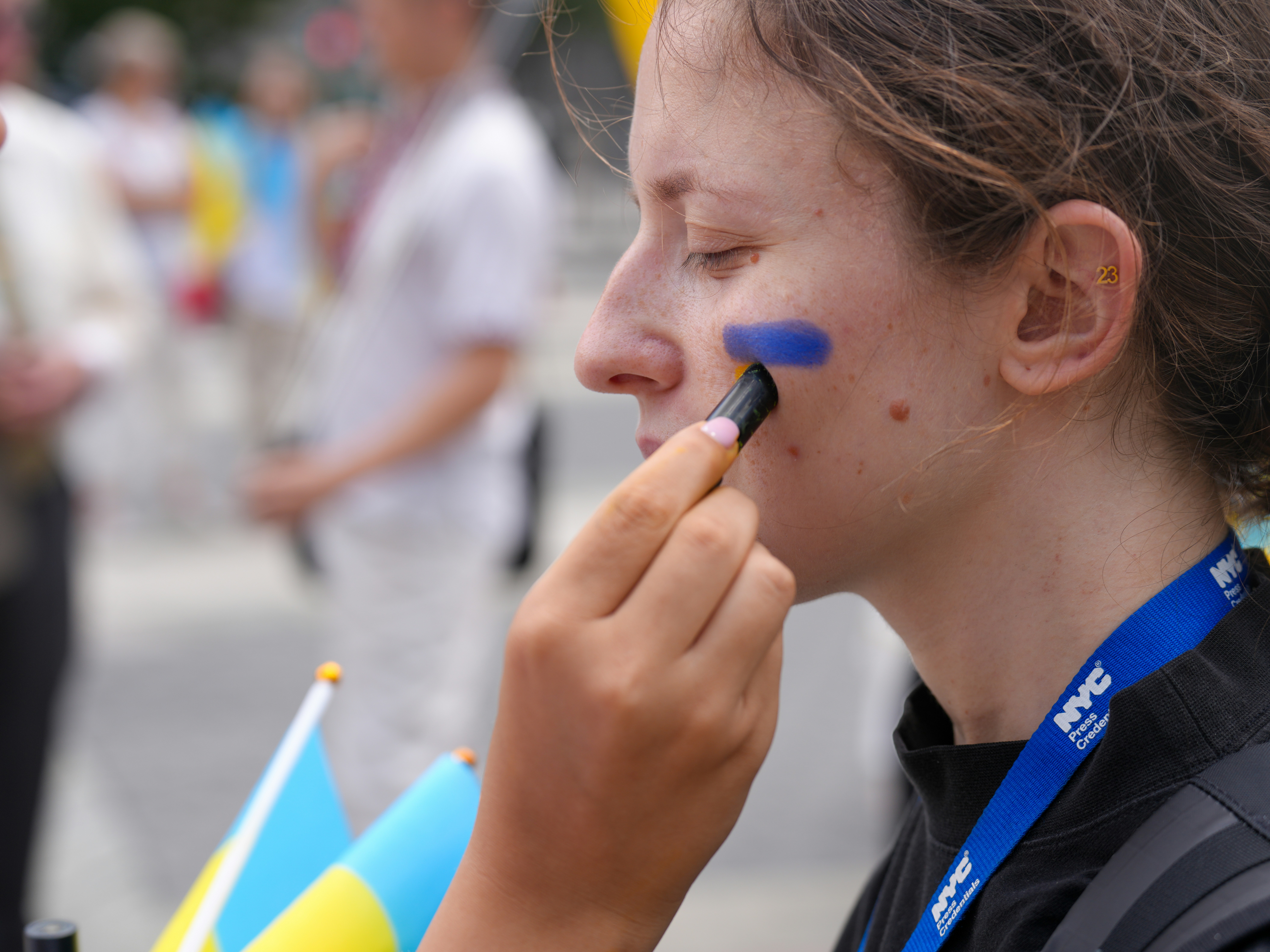 Blue Stroke of Focus: Close-up of a Makeup Moment at a Street Event