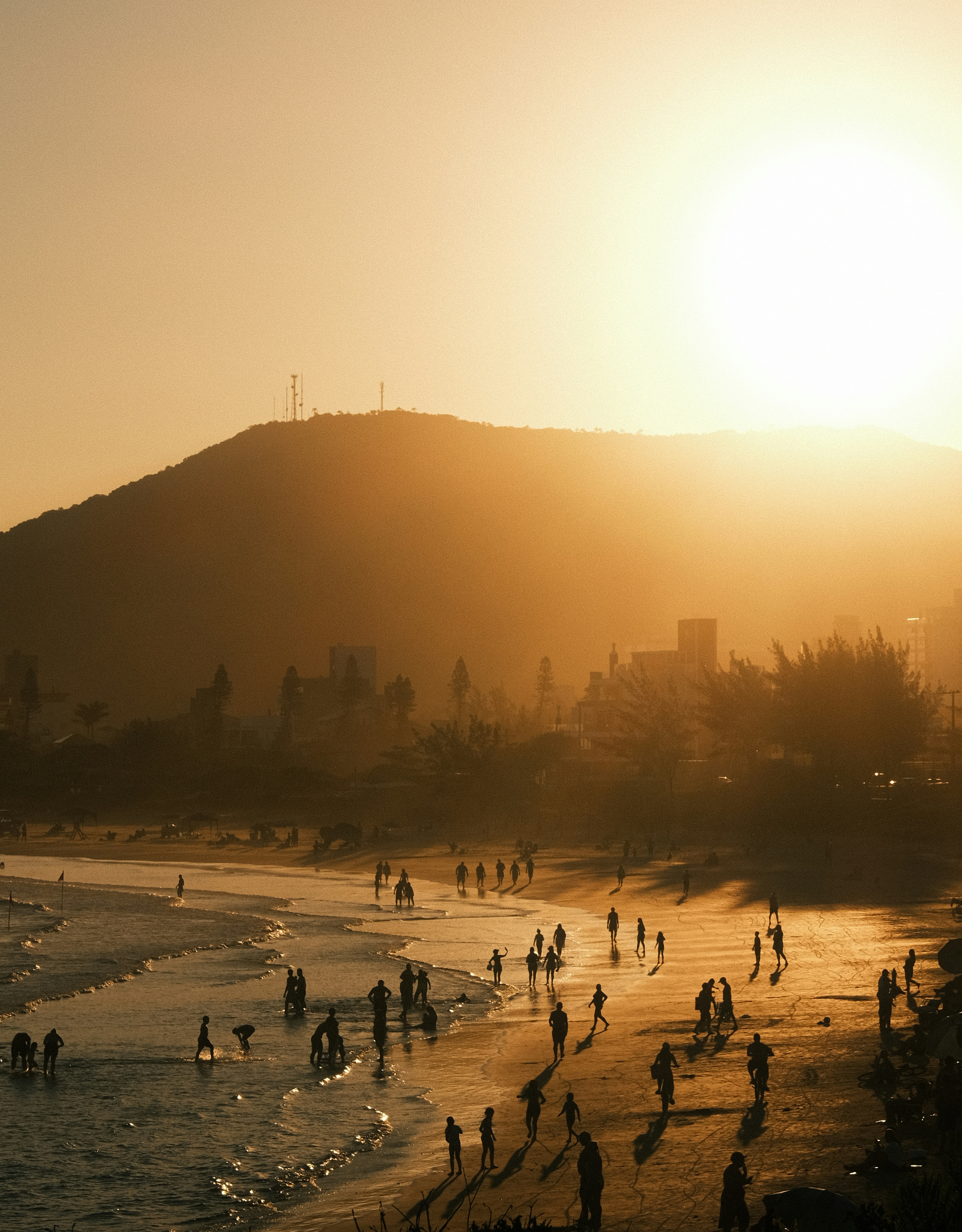 Golden Coastline at Sunset: People Silhouetted Along the Shifting Shore