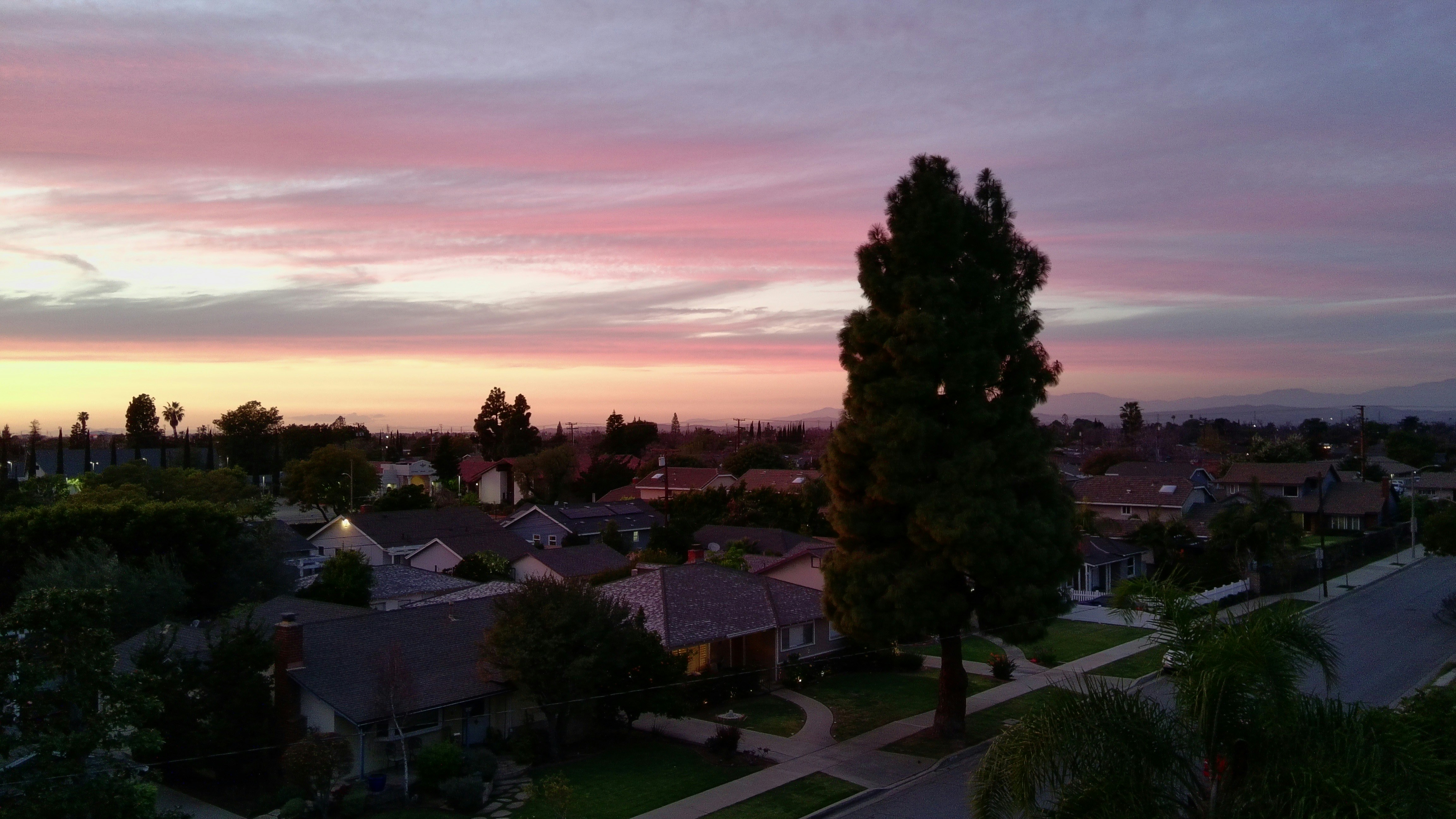 Pink and orange sky over suburban rooftops at sunset