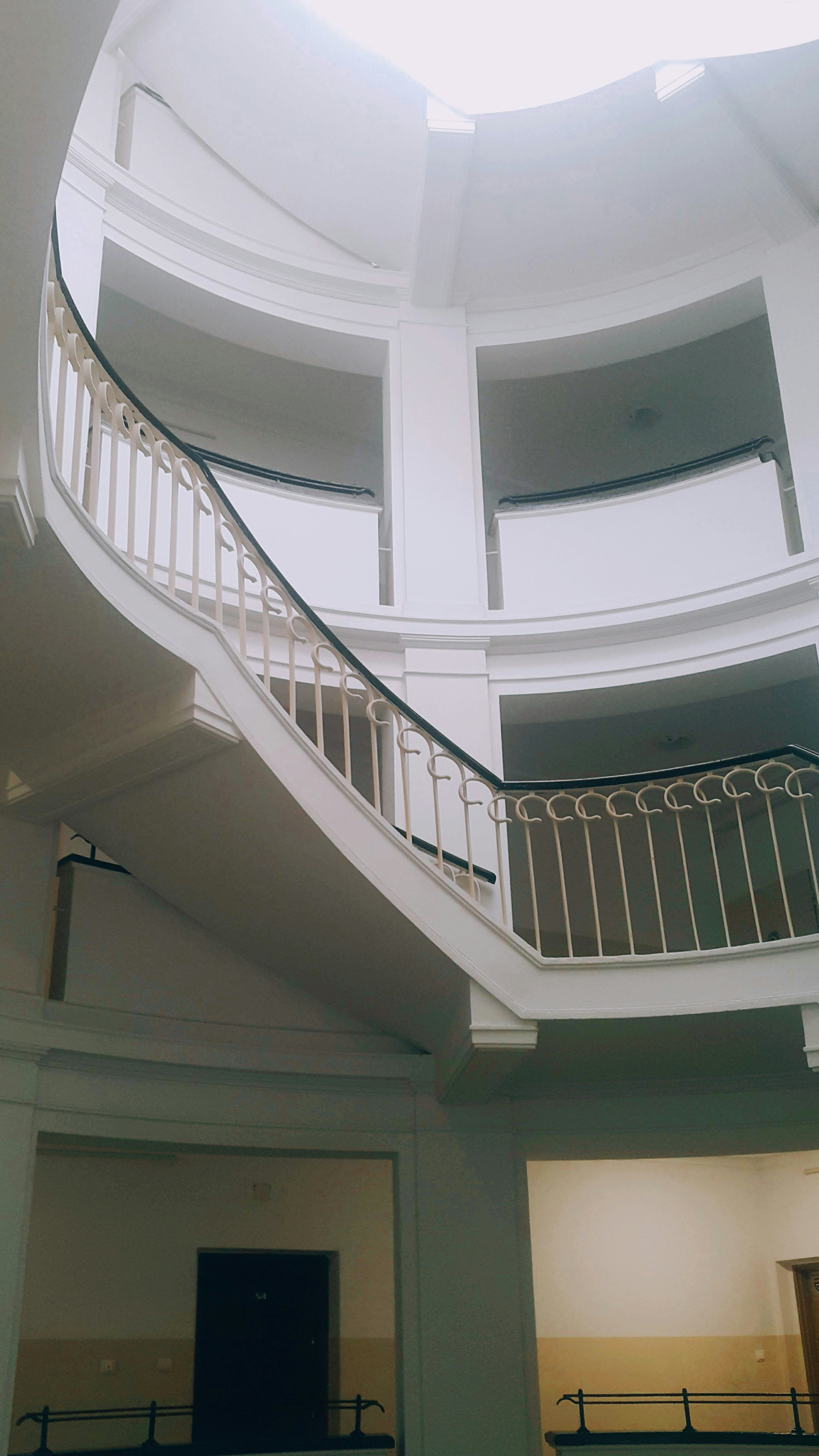 Curving white staircase with railings inside building