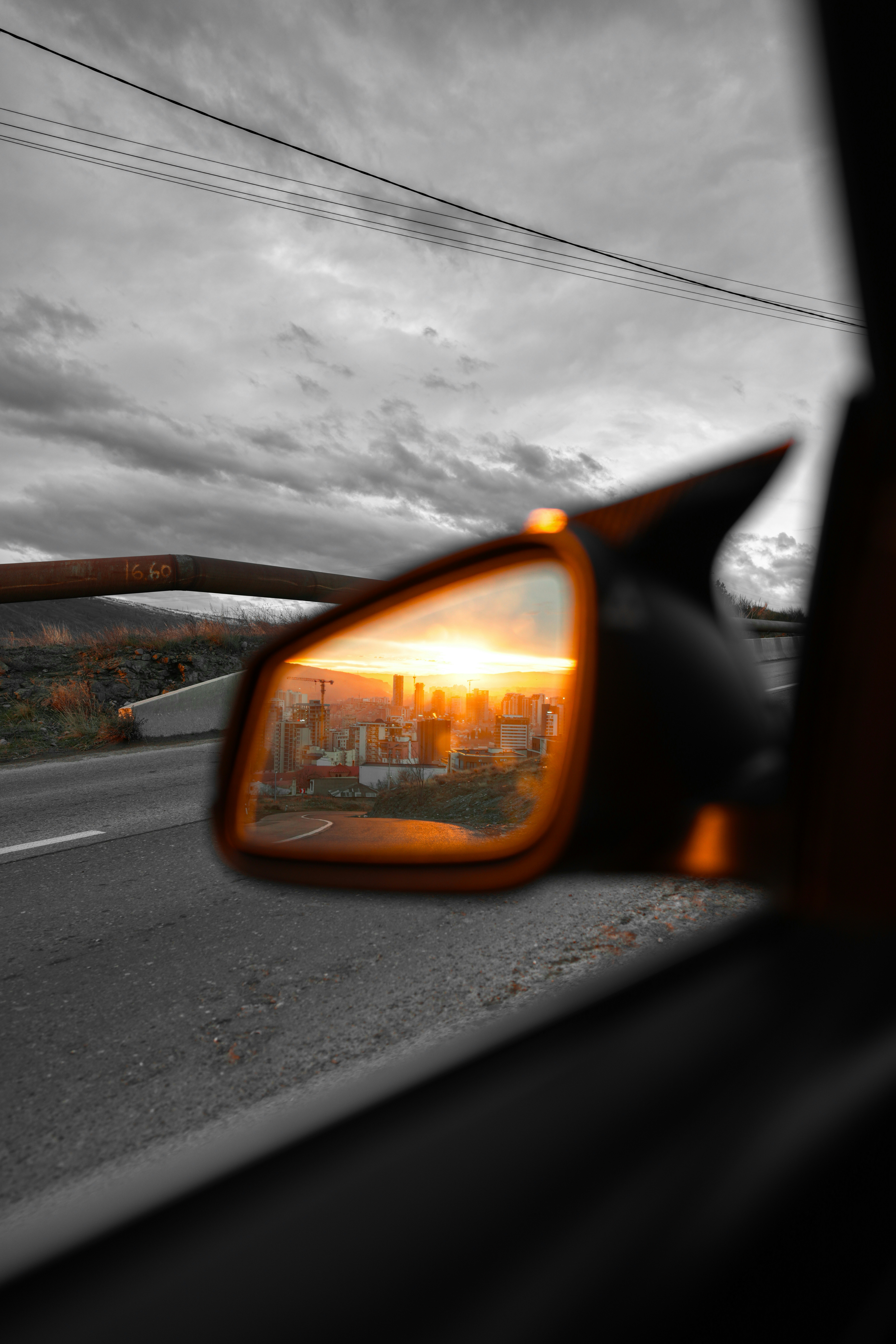 Sunset City Reflected: A Car's Orange Side Mirror Captures the Horizon