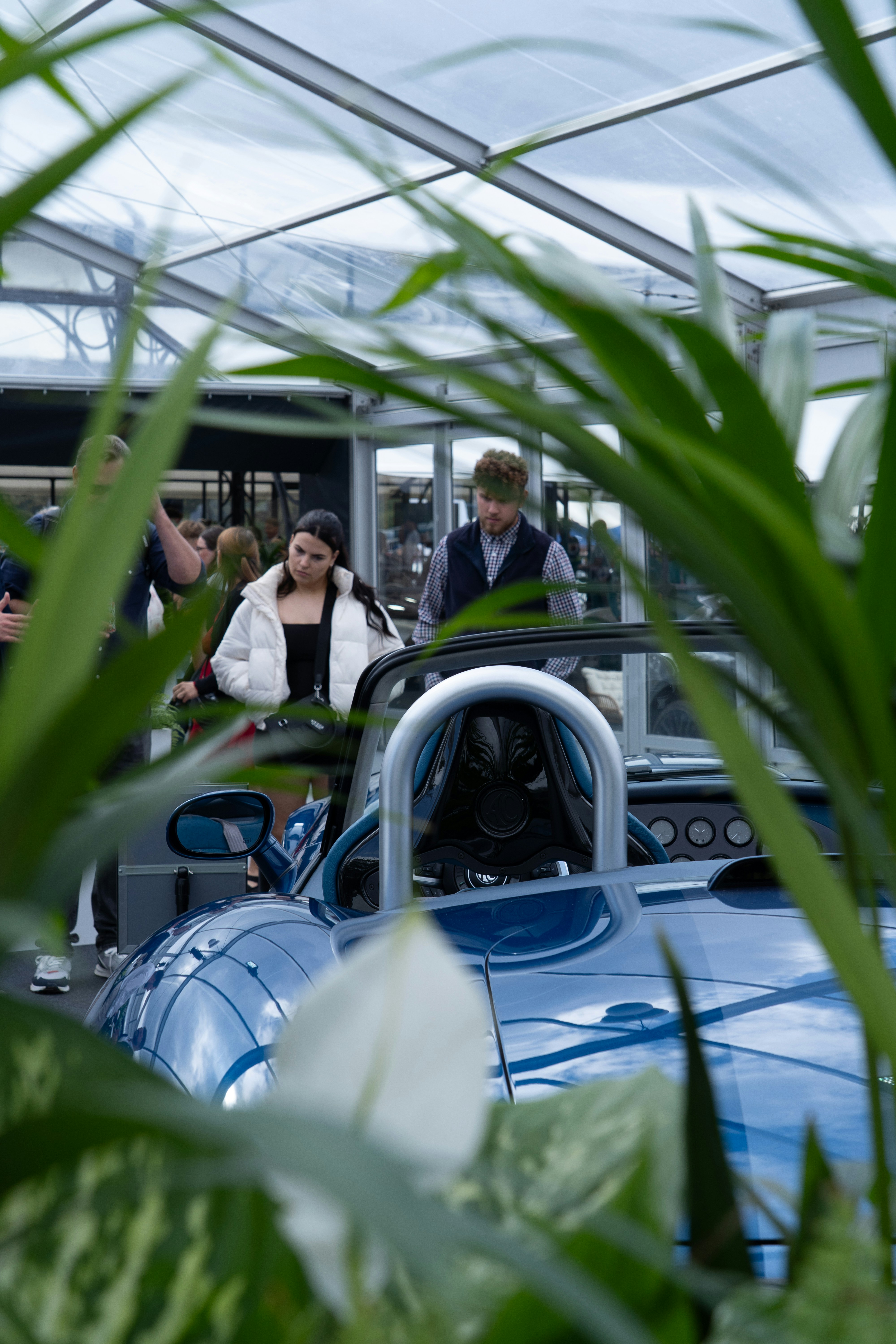 Blue Roadster Under Glass: People Pause Behind a Classic Convertible