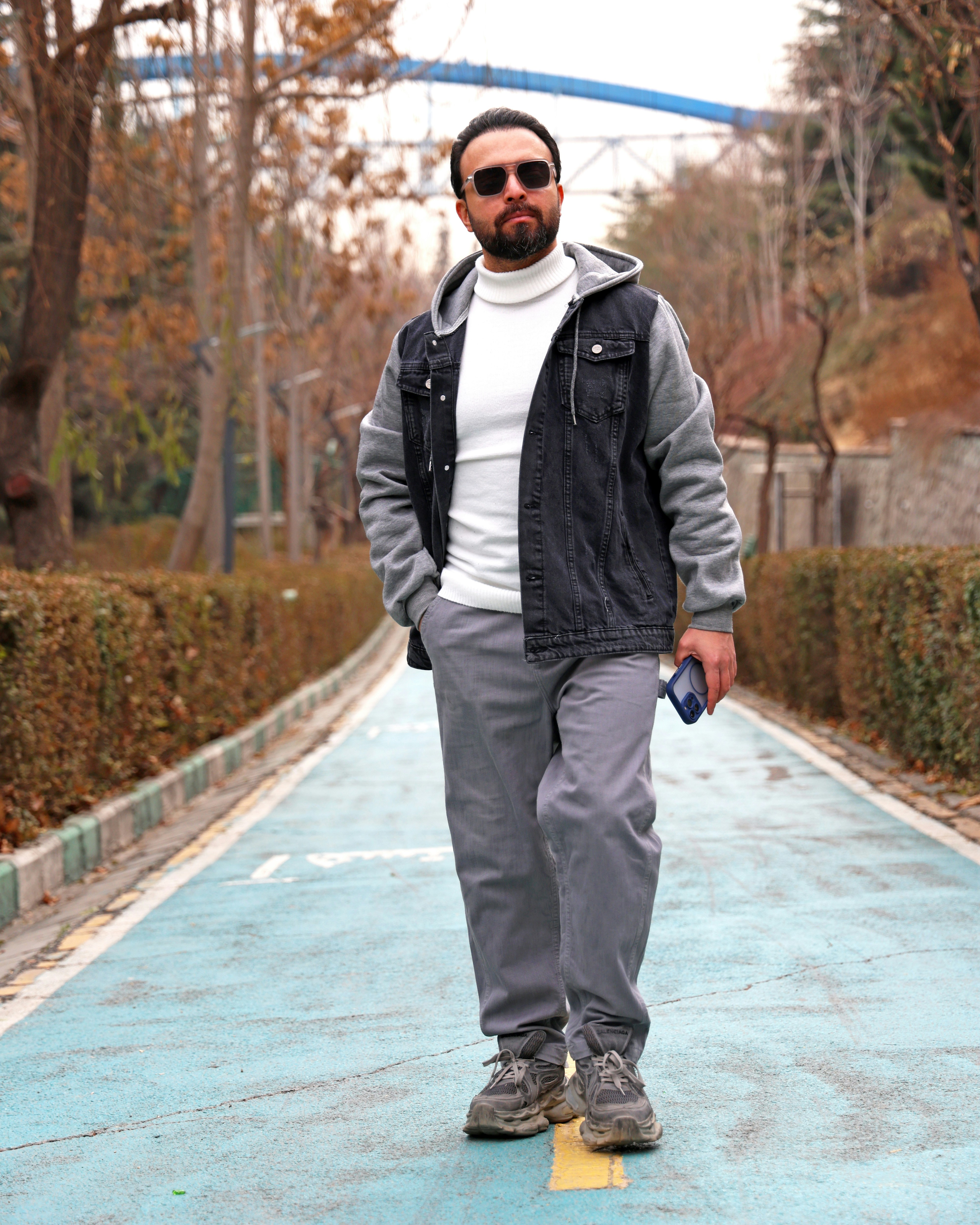 Urban Confidence: A man in a two-tone jacket strides down a pale-blue path