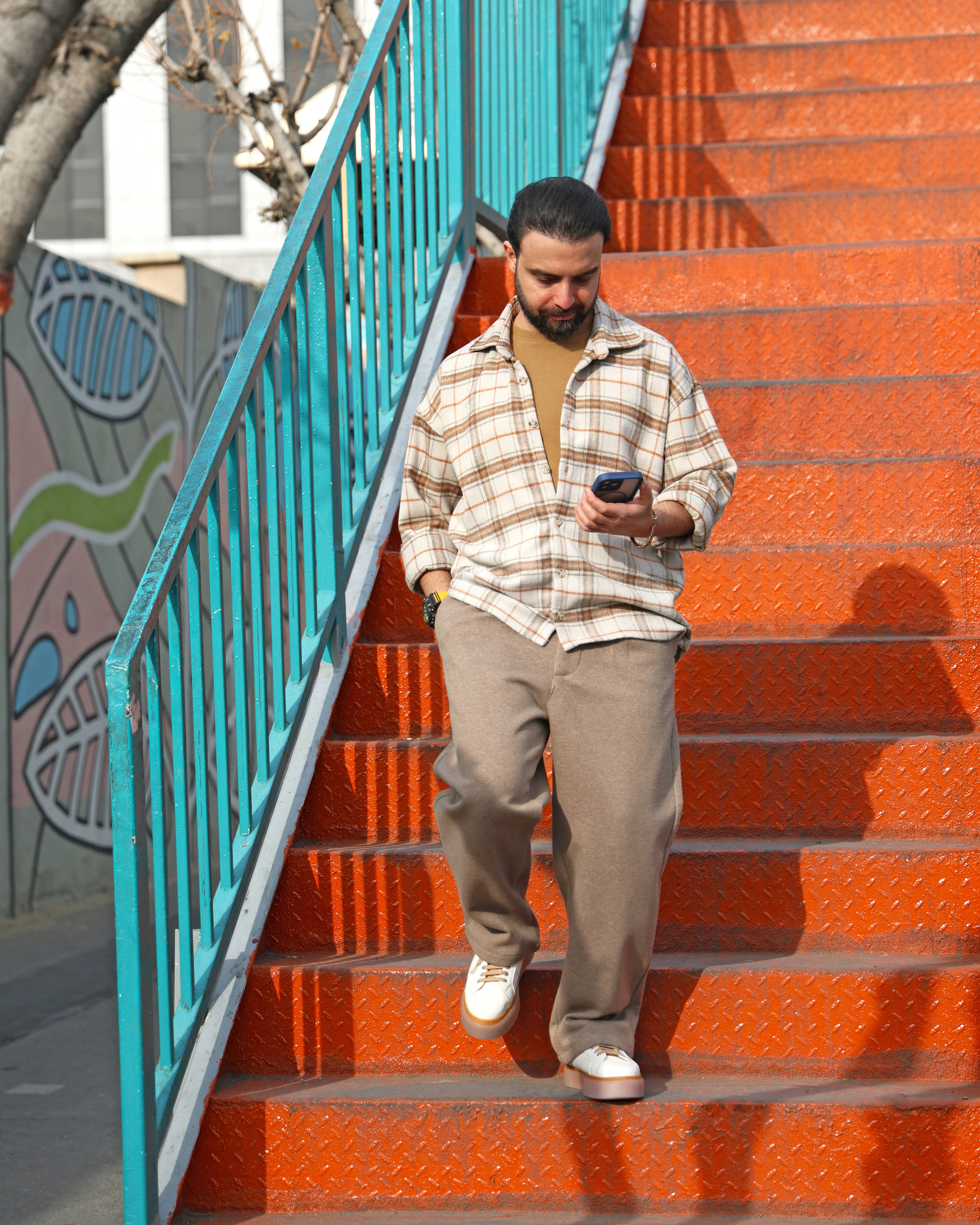 Staircase Stroll: A Quiet Moment with a Phone on Bright Orange Steps