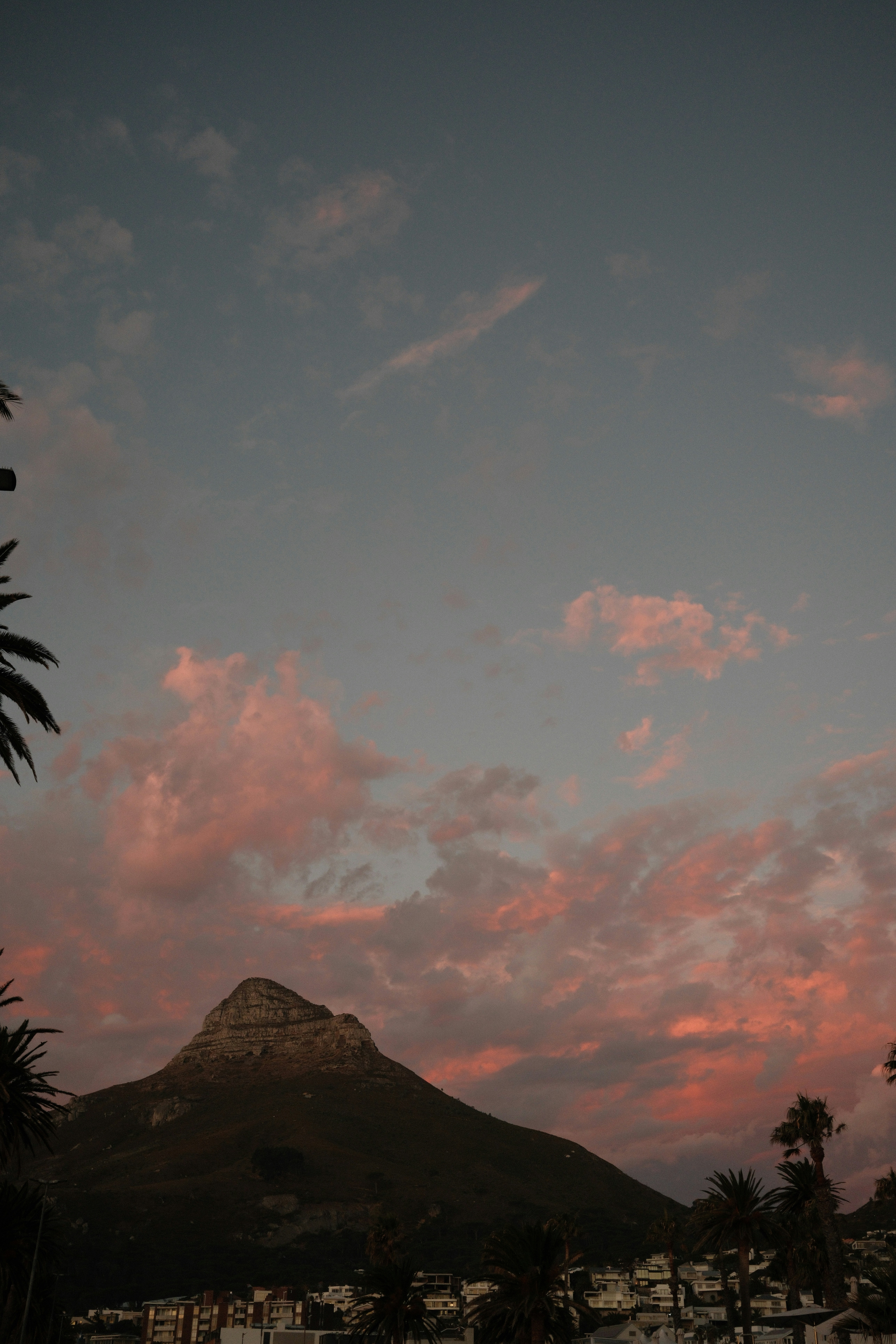 Dusk Over a Quiet Valley: The Mountain Silhouette Beneath a Coral Sky