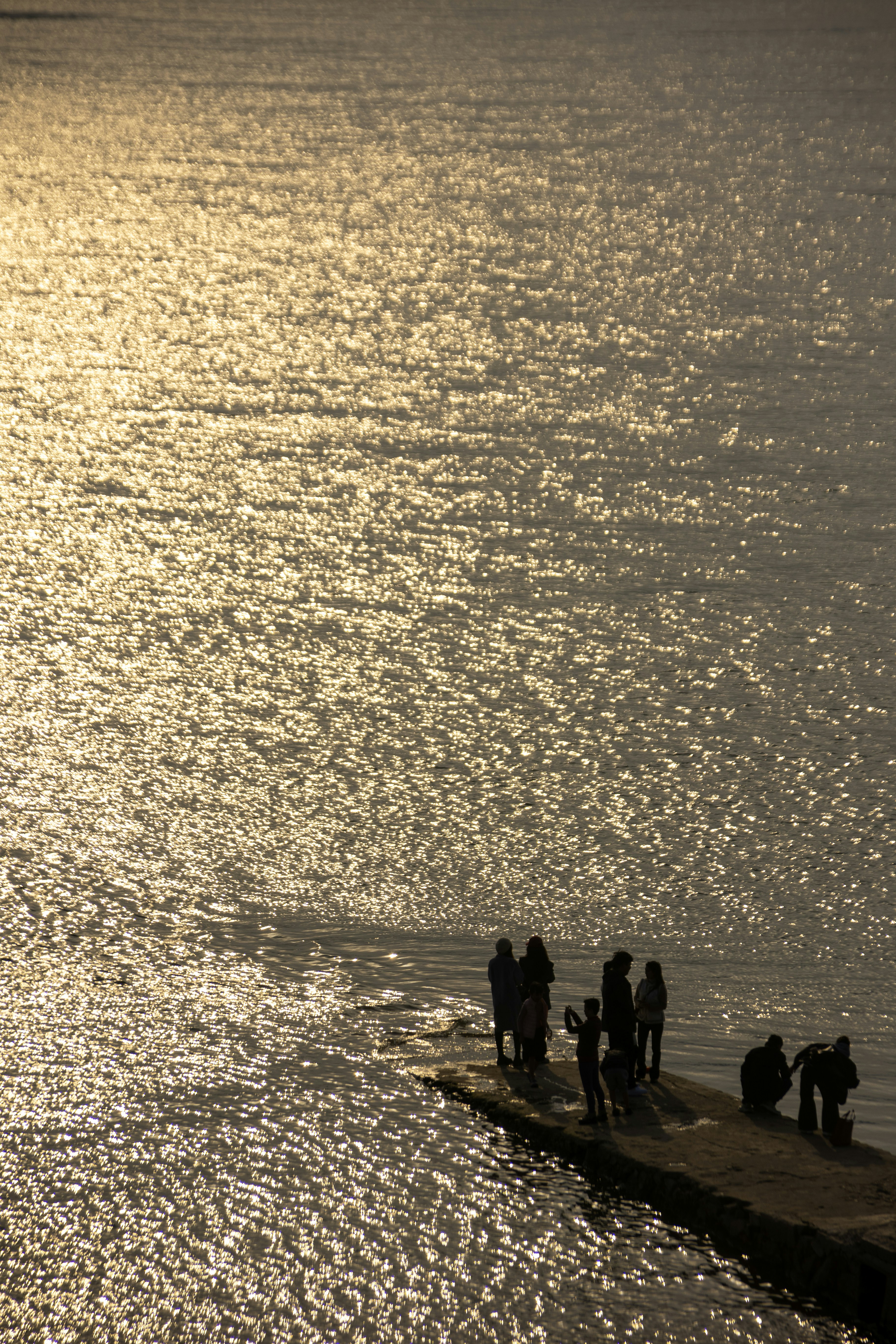 Sunlit silhouettes on a pier trimming the horizon