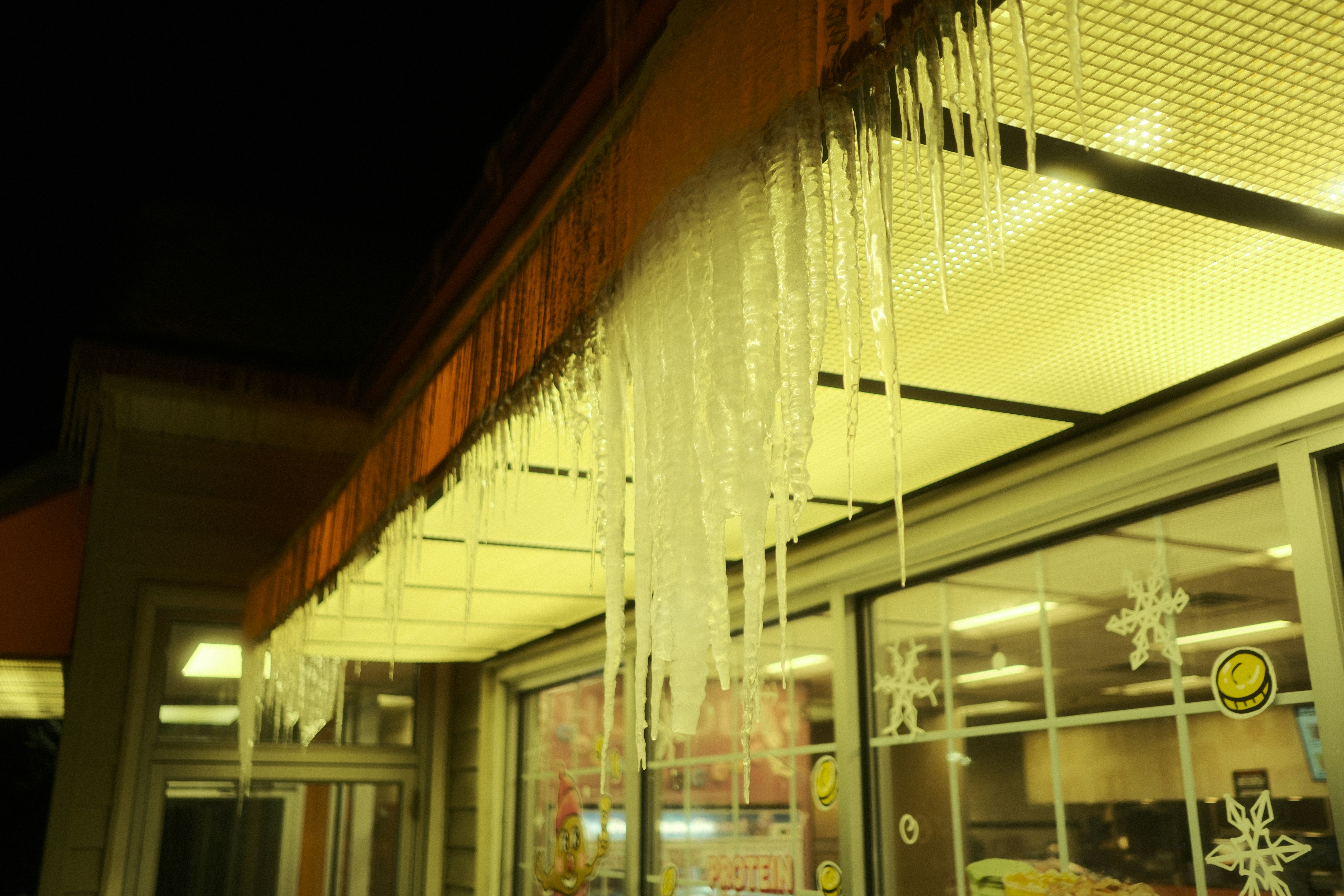 Icicles at Midnight: Warm Light over a Snowflake‑Adorned Storefront