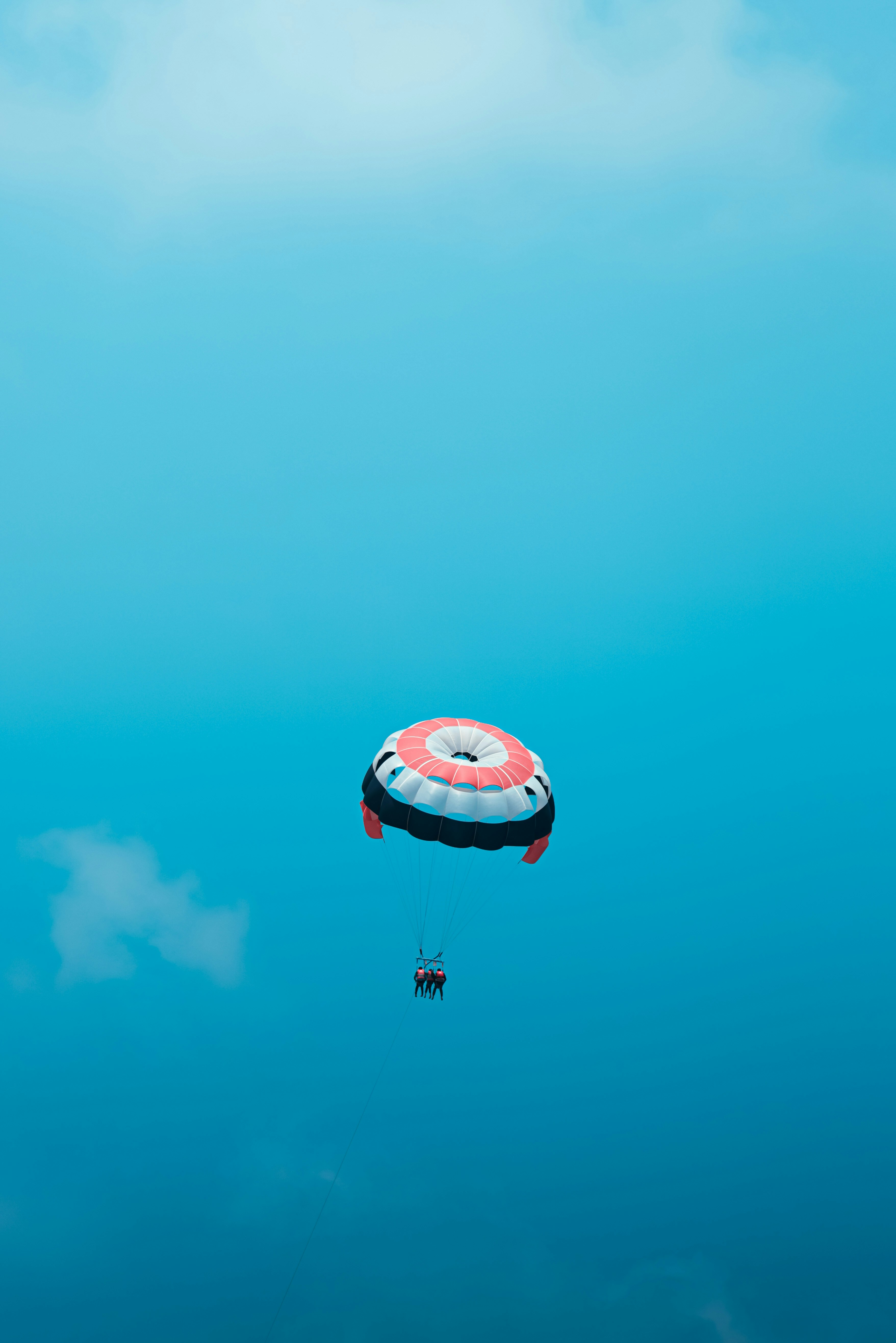 Rising to the Sky: A Parachute Descent Beneath a Vivid Blue
