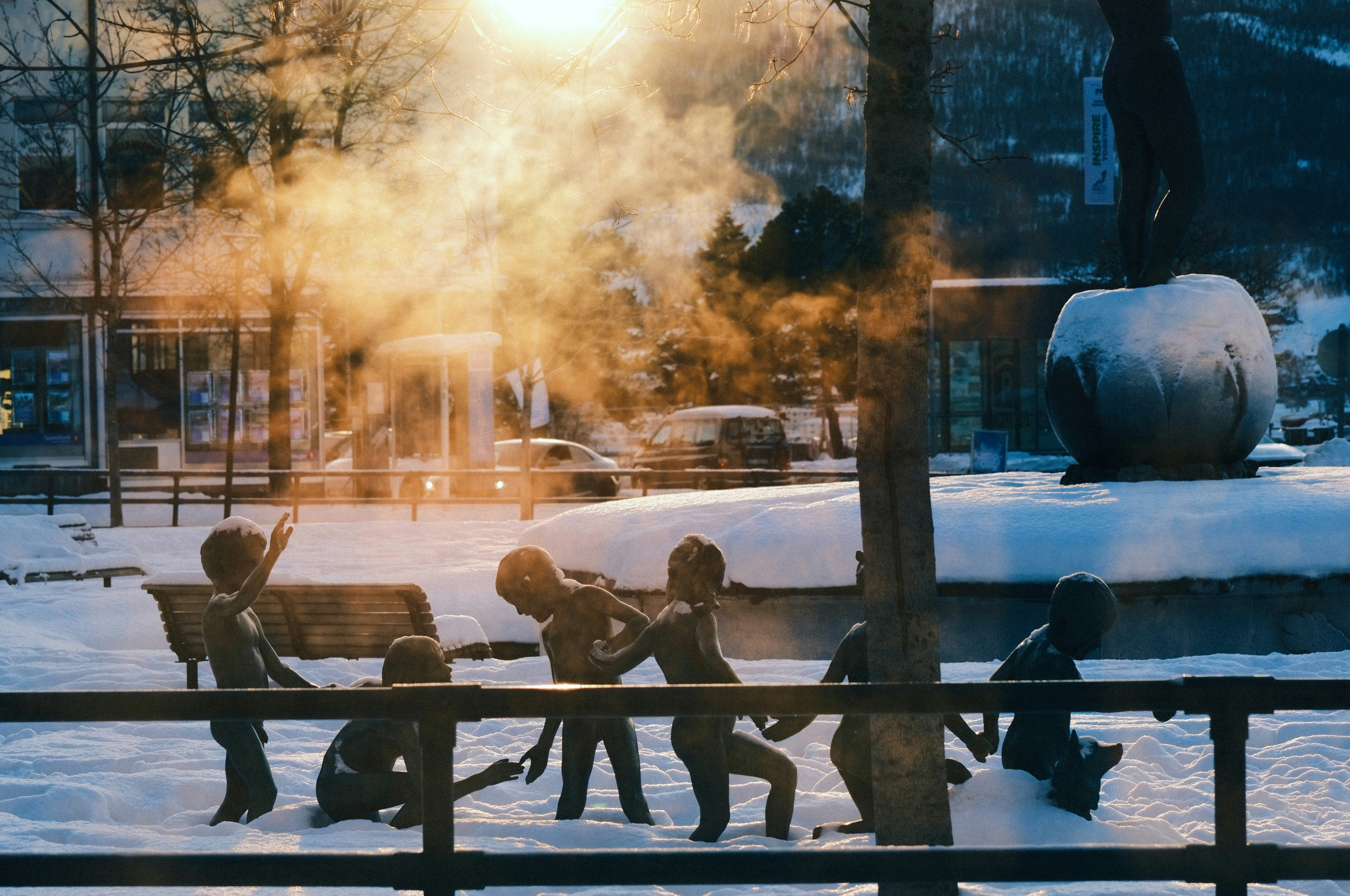 Snowy playground: children at play amid rising steam and urban dusk