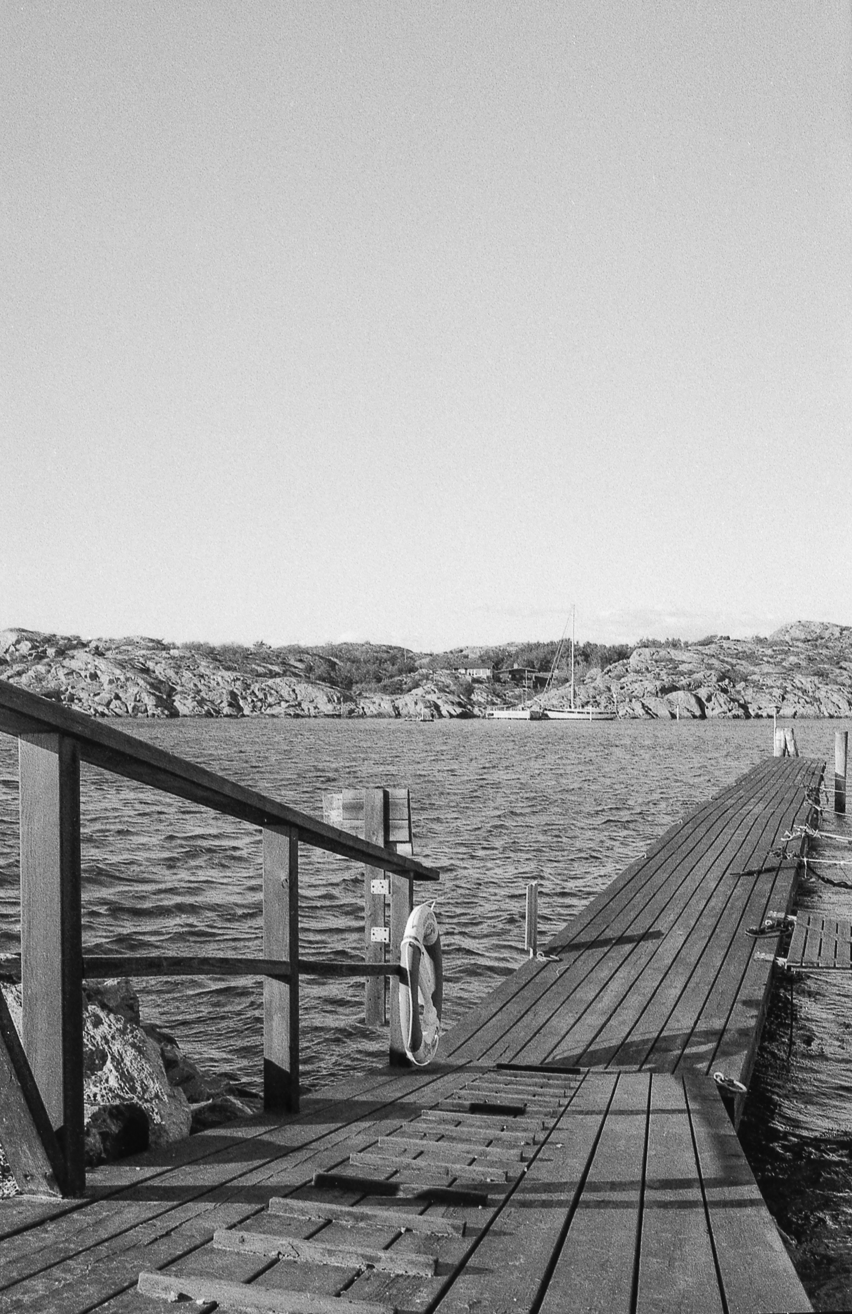Wooden pier leading to the water with rocky coastline.