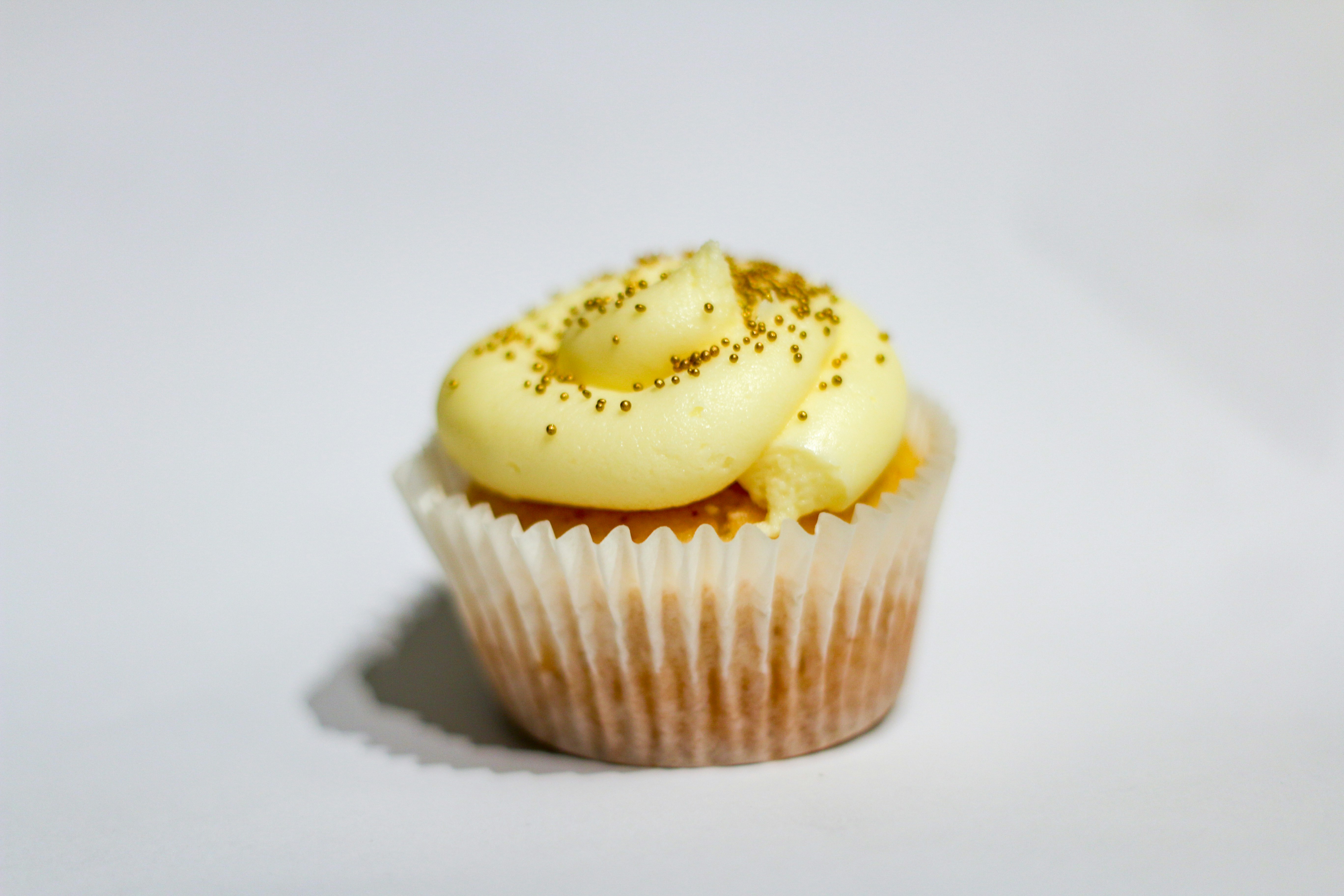 Single cupcake centerpiece: vanilla frosting swirls under soft shadow