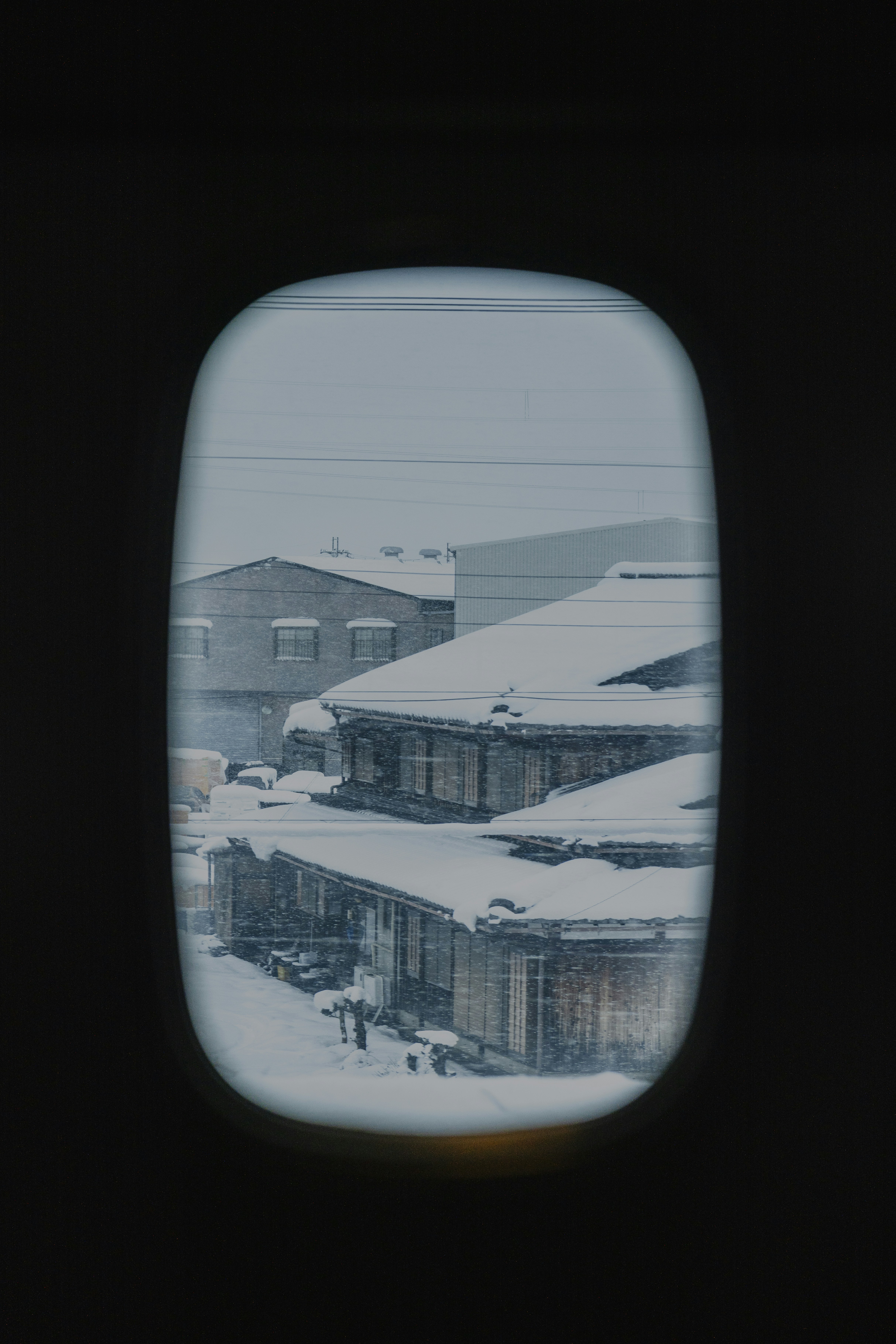 Snowbound Window: Quiet Village Through an Airy Oval