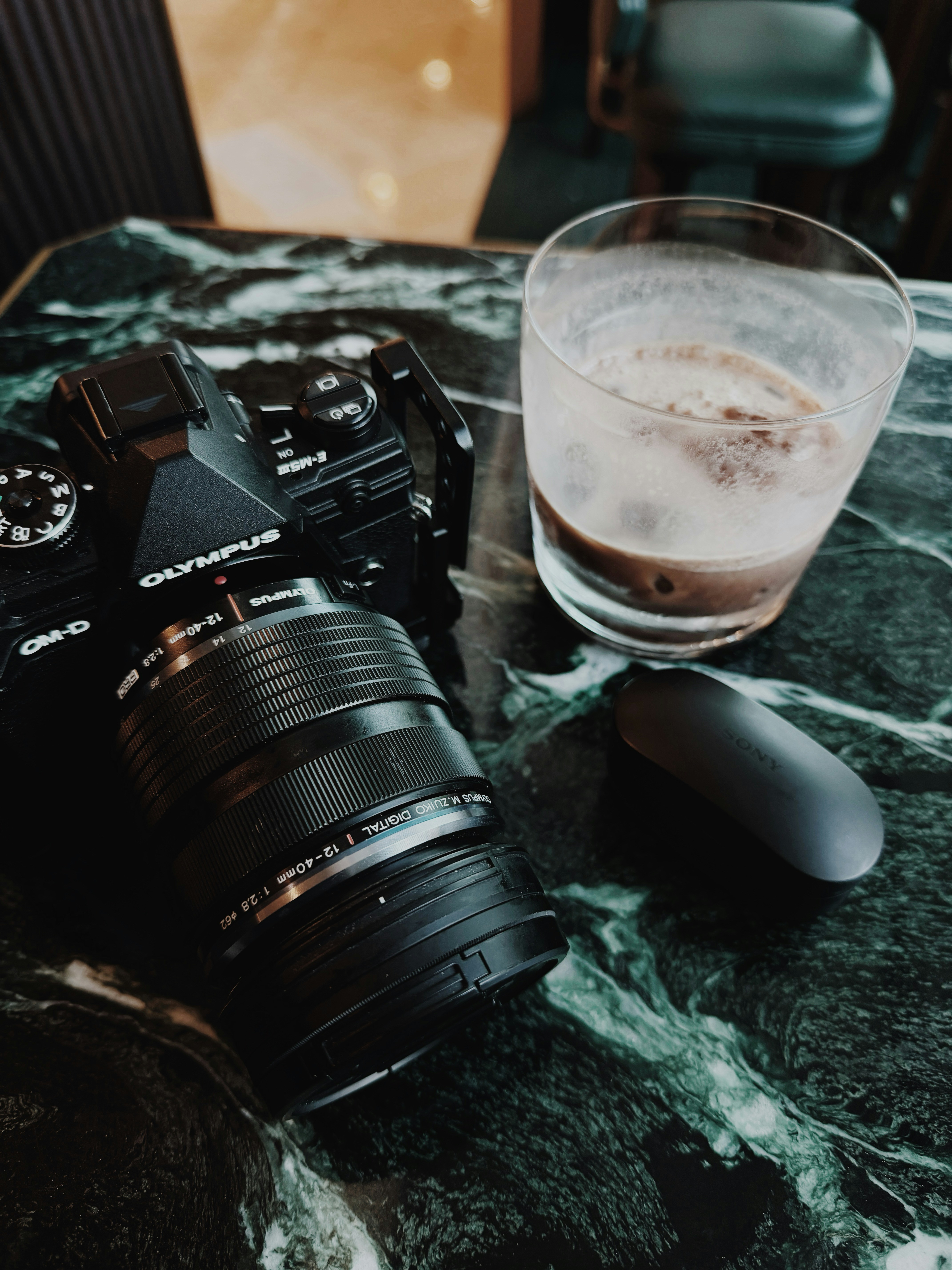 A quiet still life of a camera setup on marble and a glass of coffee