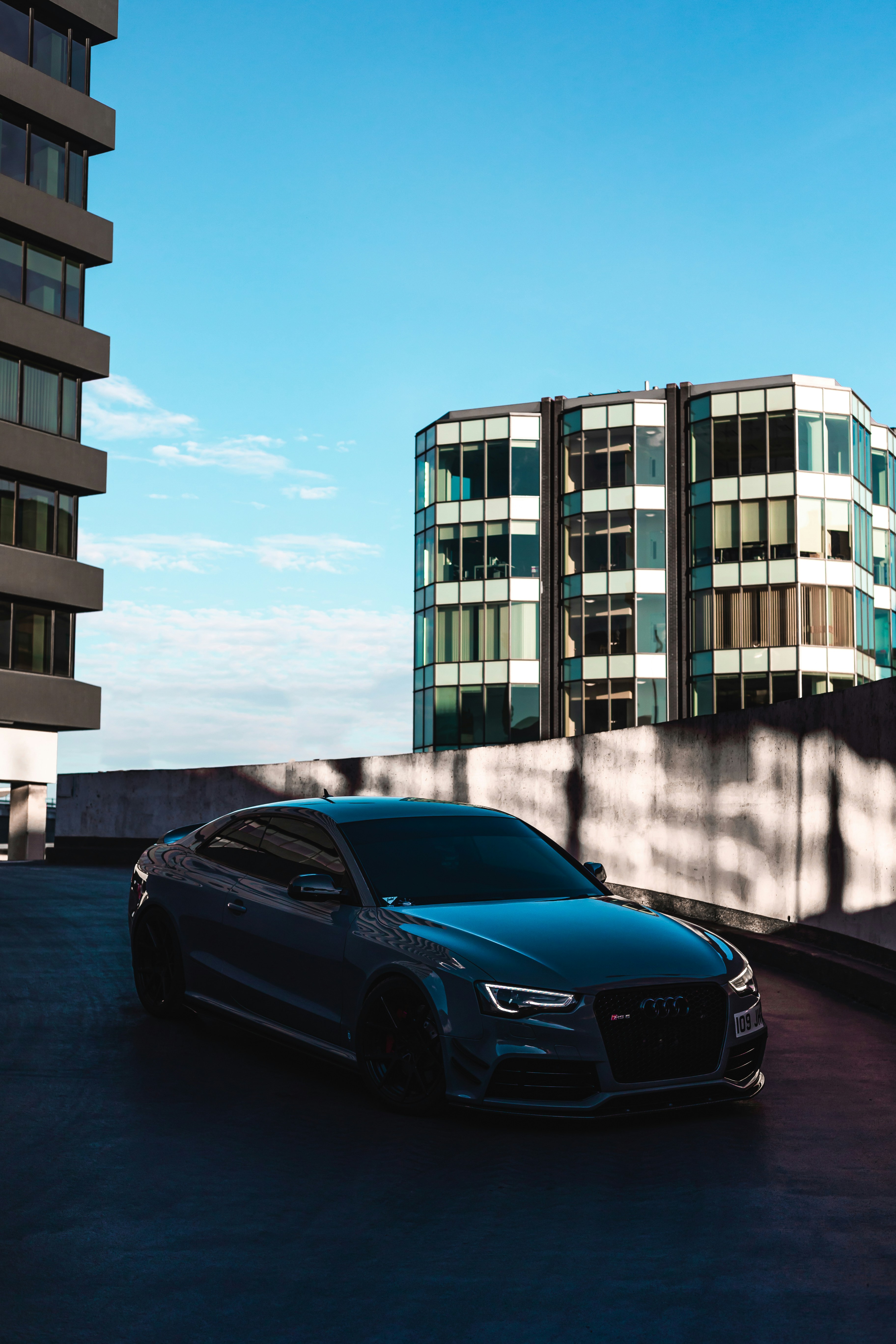 Shadowed Audi on a Rooftop Between Modern Glass and Sky